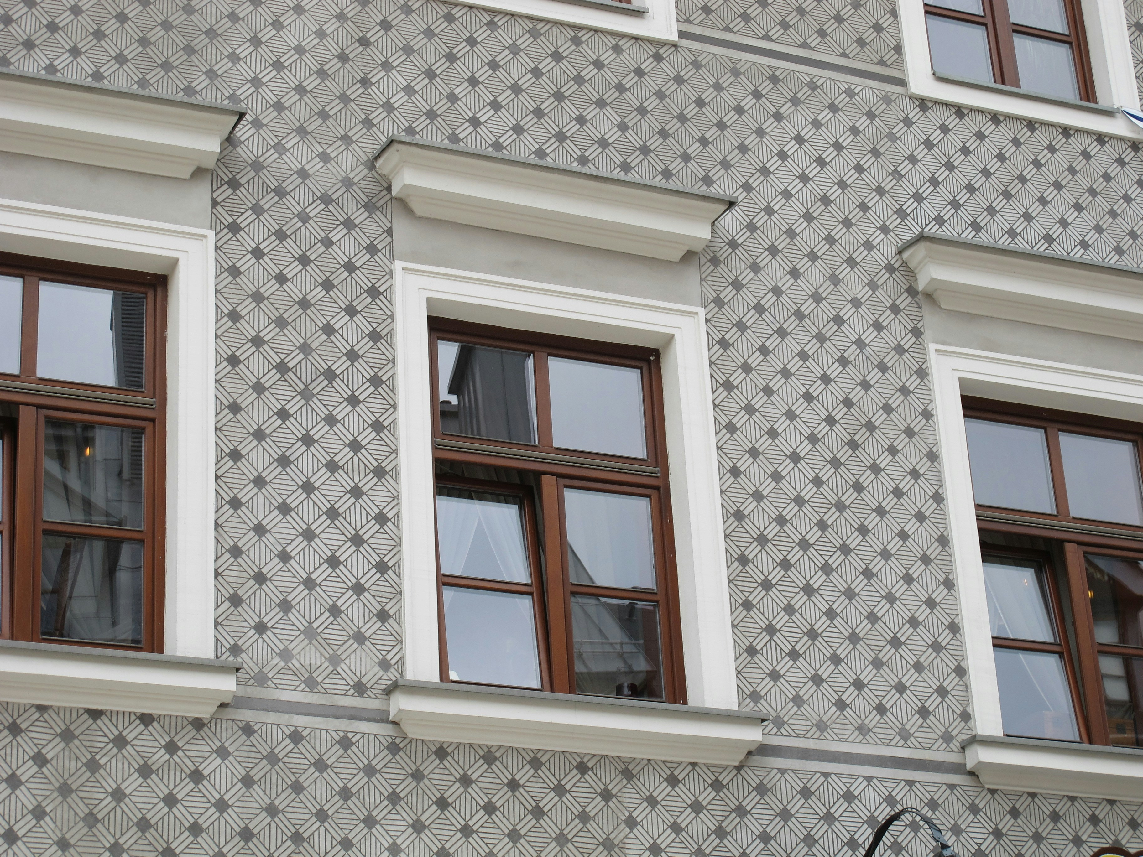 Patterned stone building facade with symmetrical wooden-framed windows.