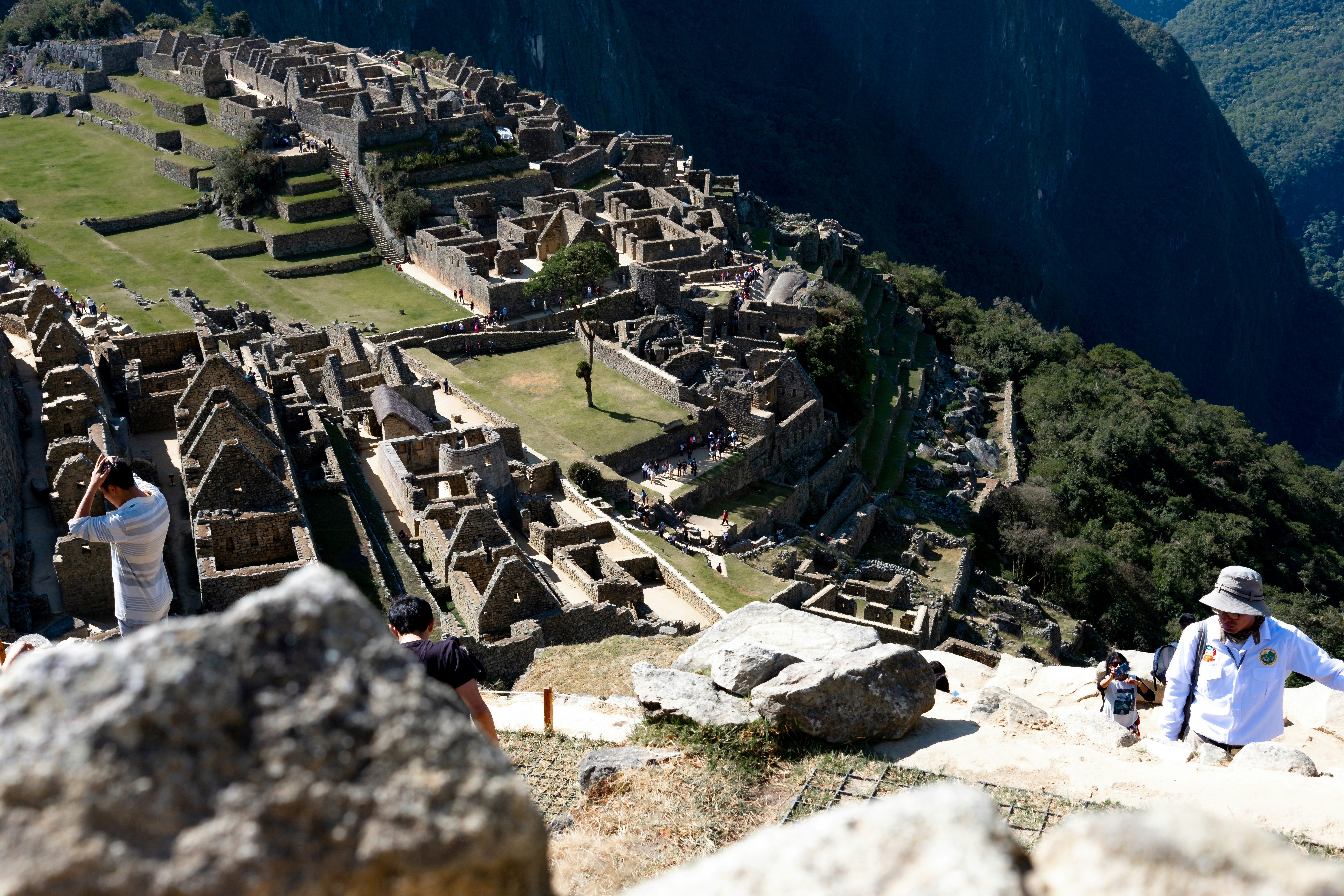 Overhead view of Machu Picchu's stone ruins surrounded by lush mountains.