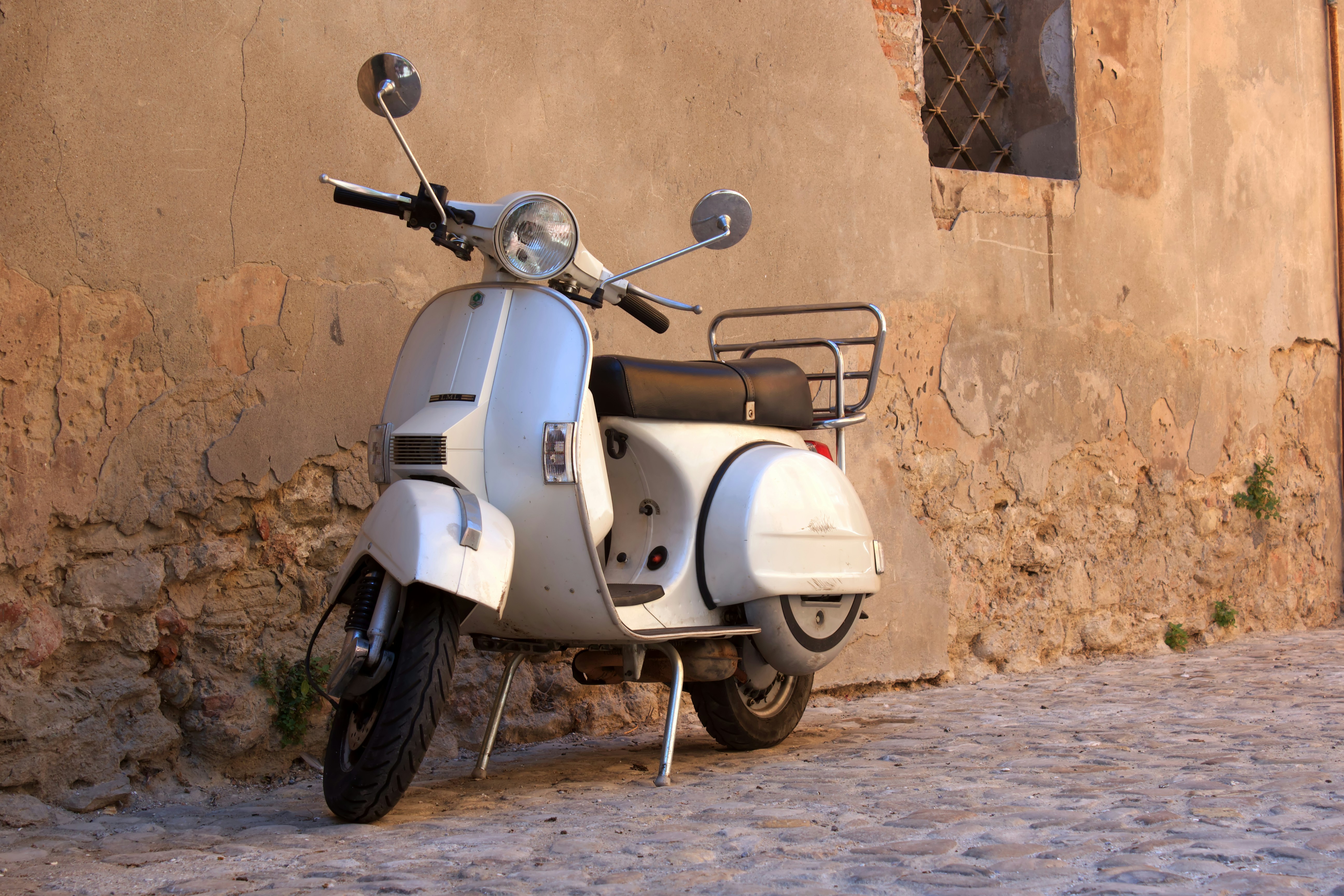 Vespa | gray and black motor scooter parked beside brown concrete wall