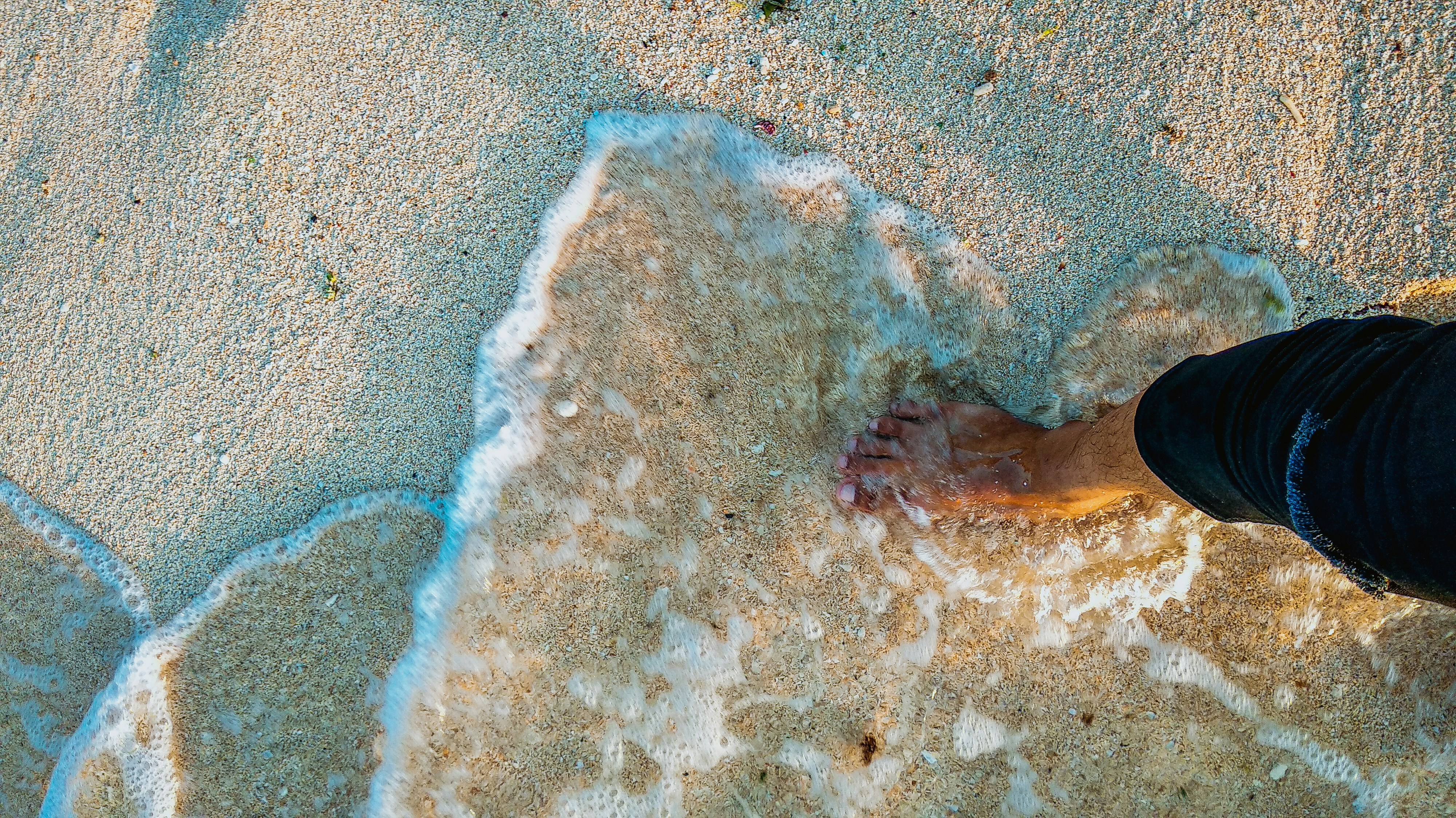 Foam and Footstep: A Beach Moment in Sunlit Sand