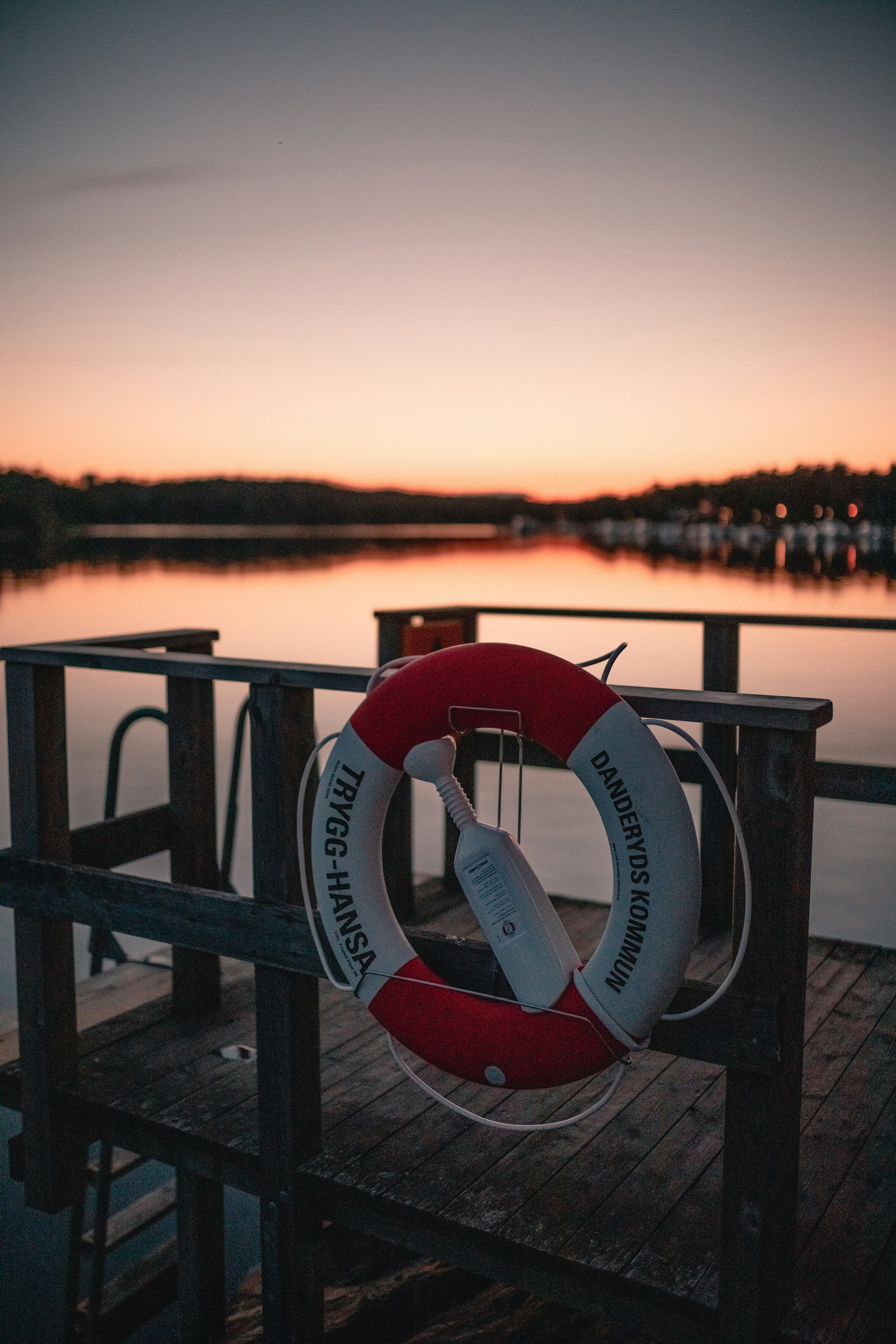 Red Lifebuoy at Dusk: A Weathered Dock Framing a Calm Lake