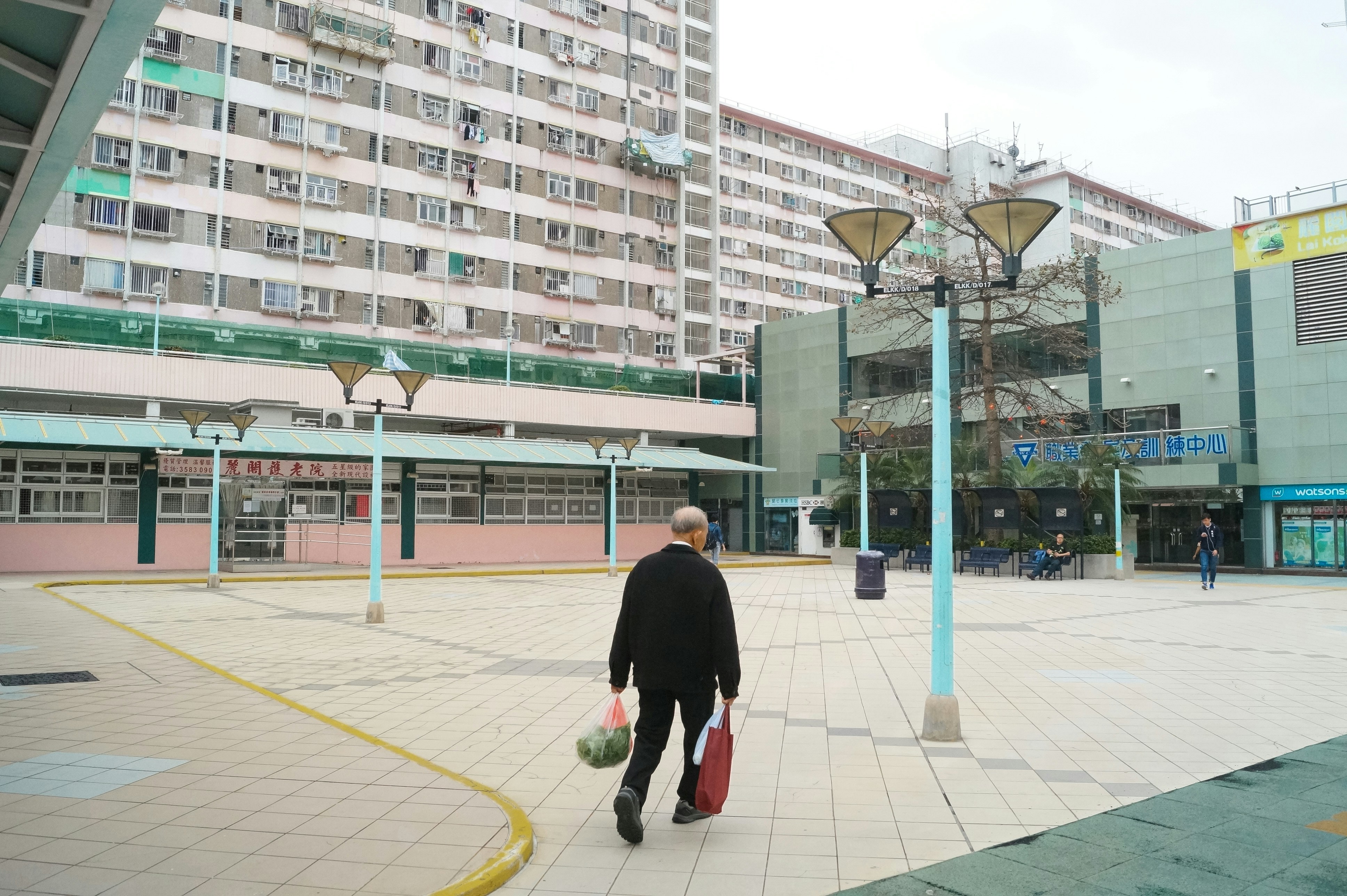 man in black long sleeve shirt and pink pants walking on sidewalk during daytime
