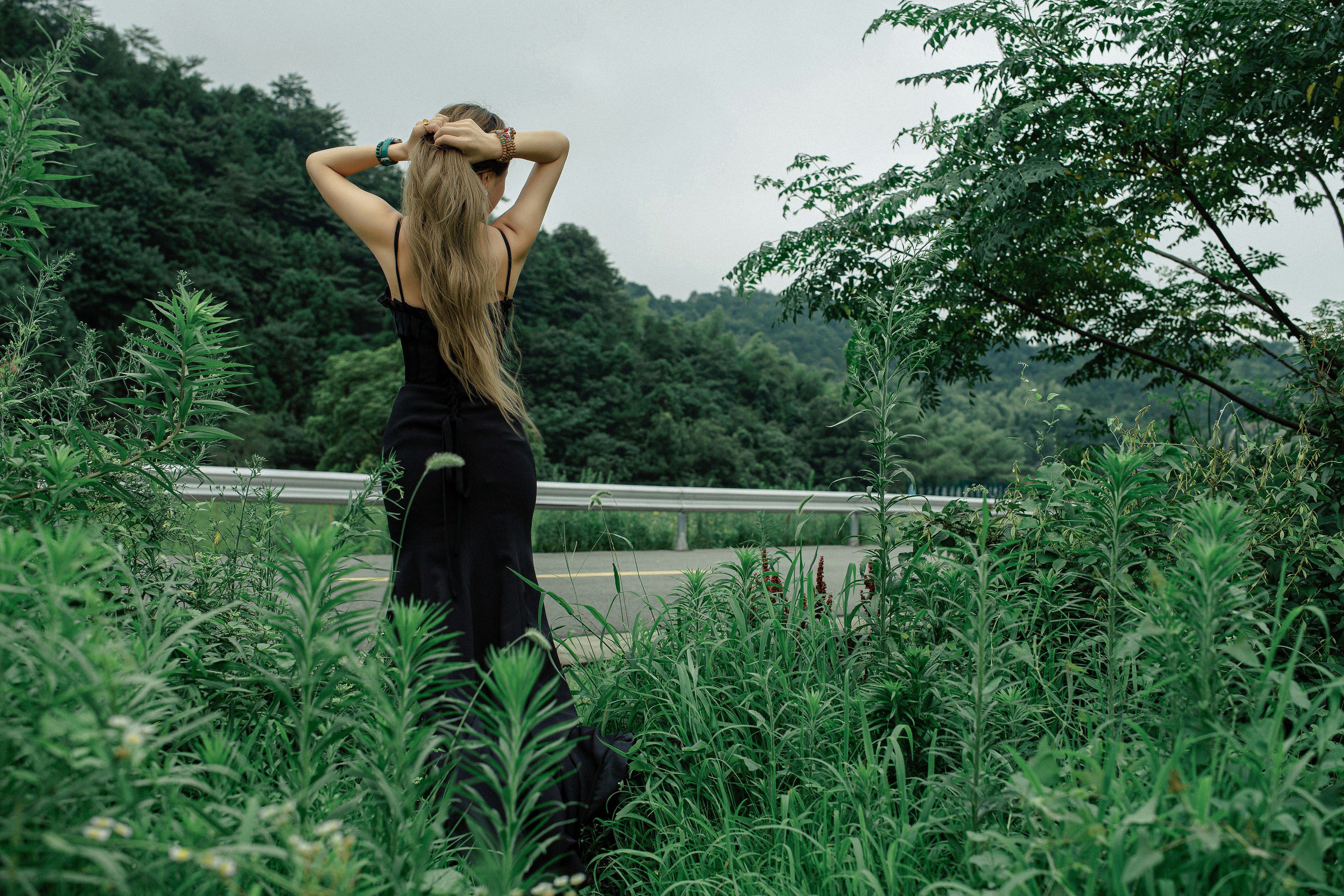 woman in black sleeveless dress standing on green grass field during daytime