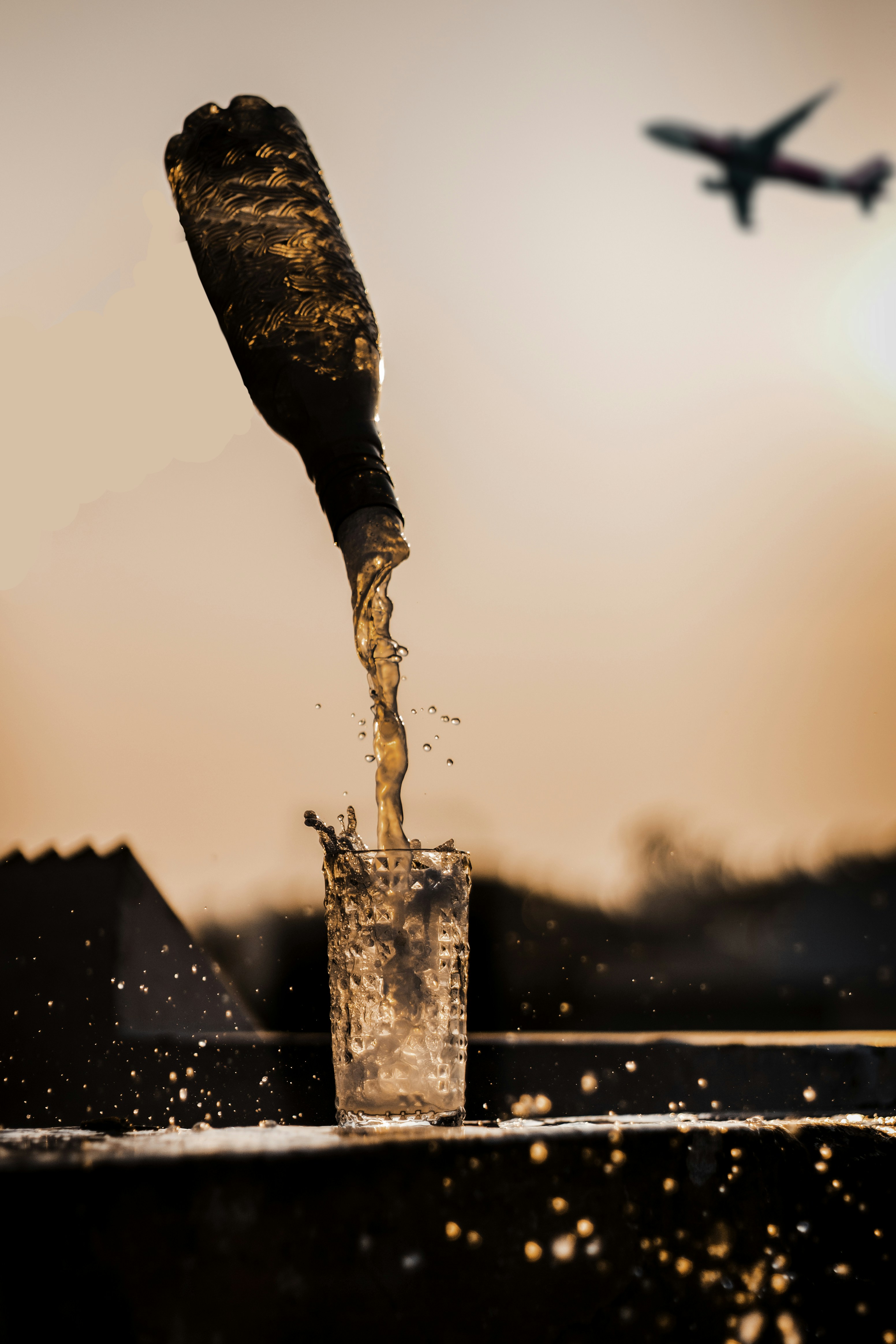 Amber Ribbon at Sunset: Pouring Light into a Glass Beneath a Passing Plane