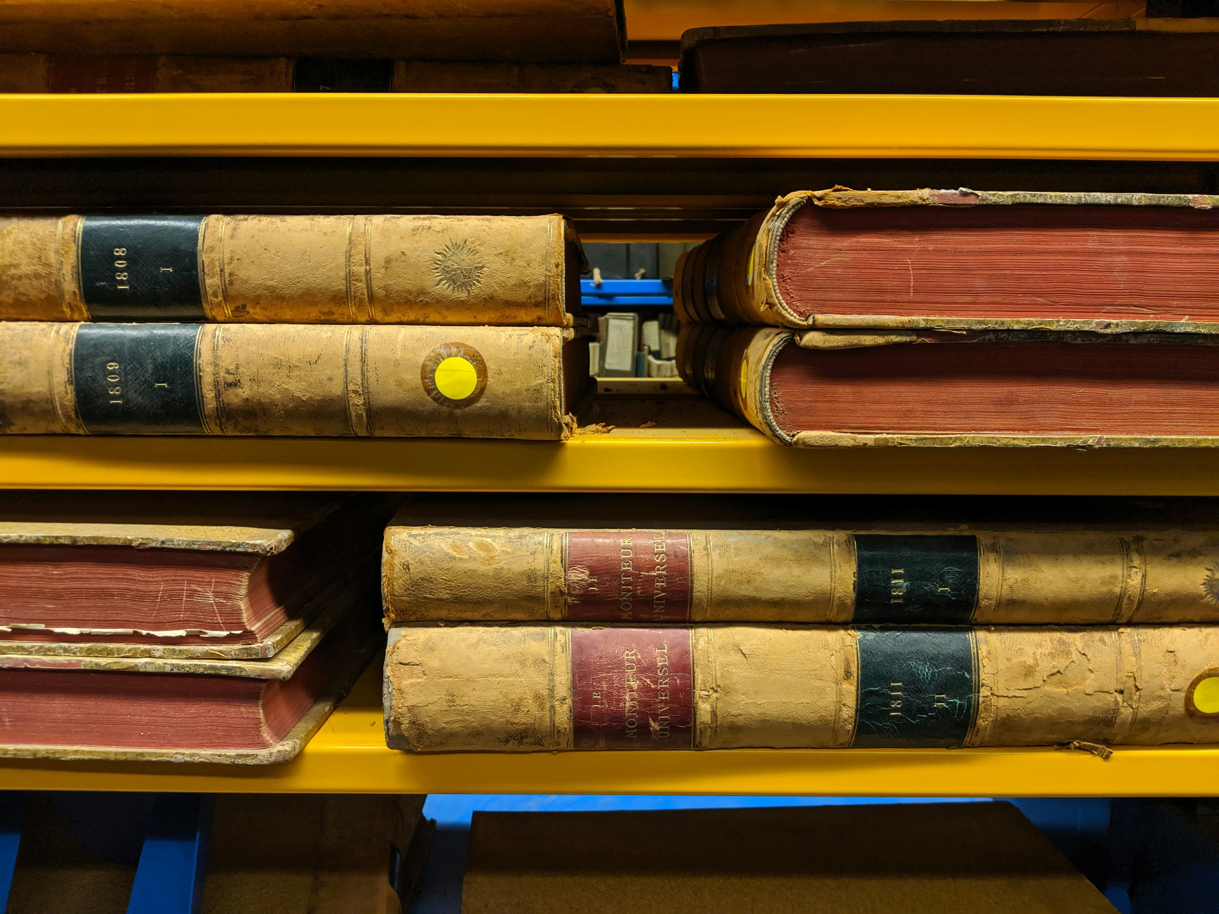 Blue Clip Between Timeworn Volumes on a Sunlit Yellow Shelf