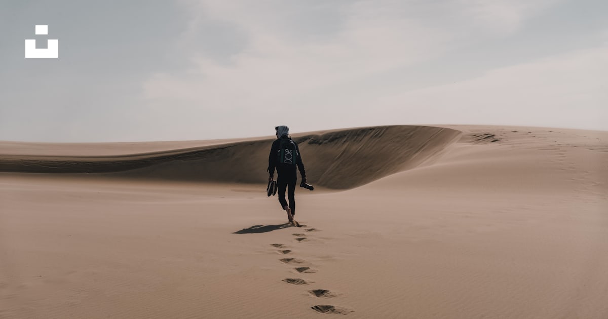 Man In Black Jacket Walking On Brown Sand During Daytime Photo Free