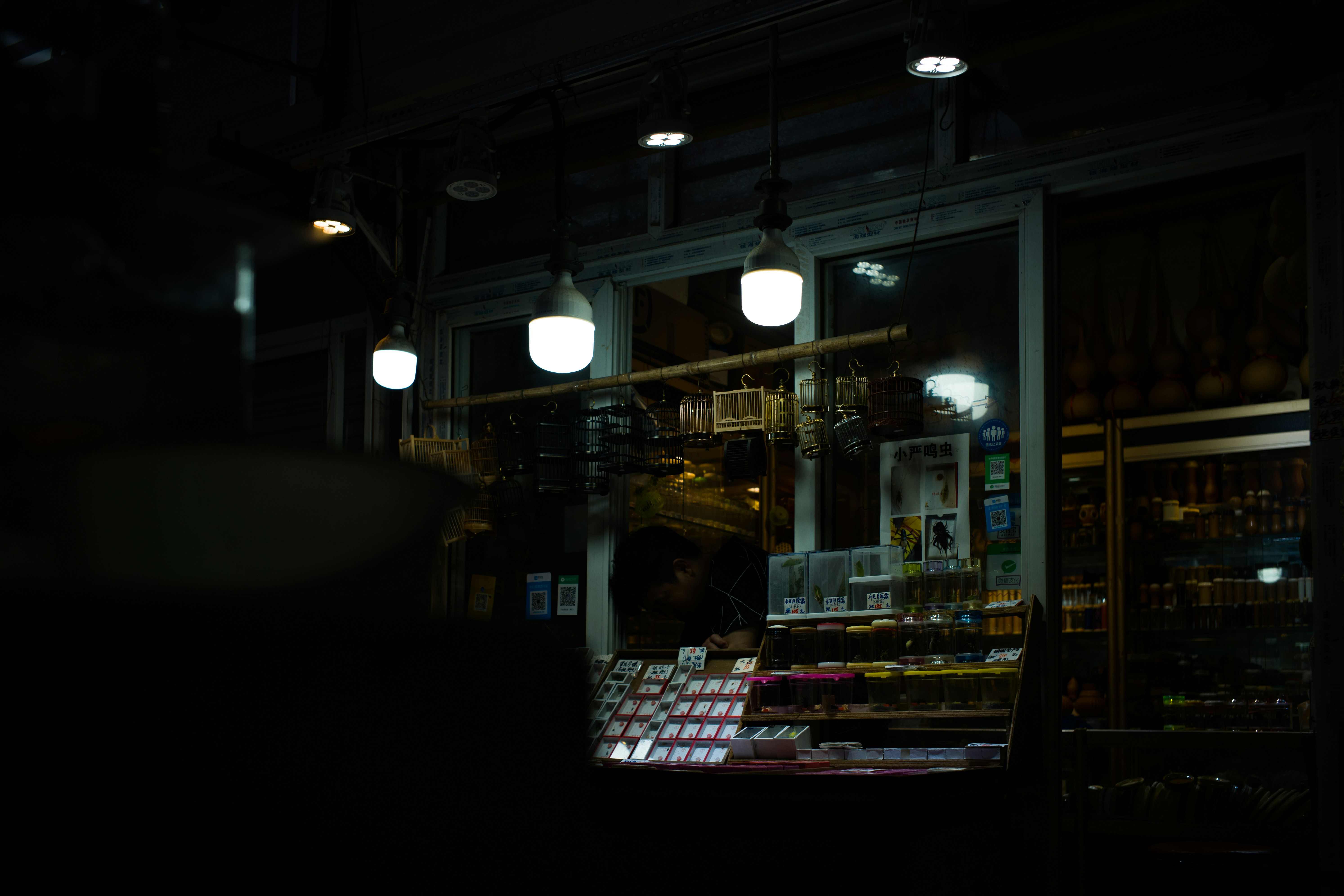 Dimly lit market stall showcasing an array of colorful goods under glowing light fixtures.