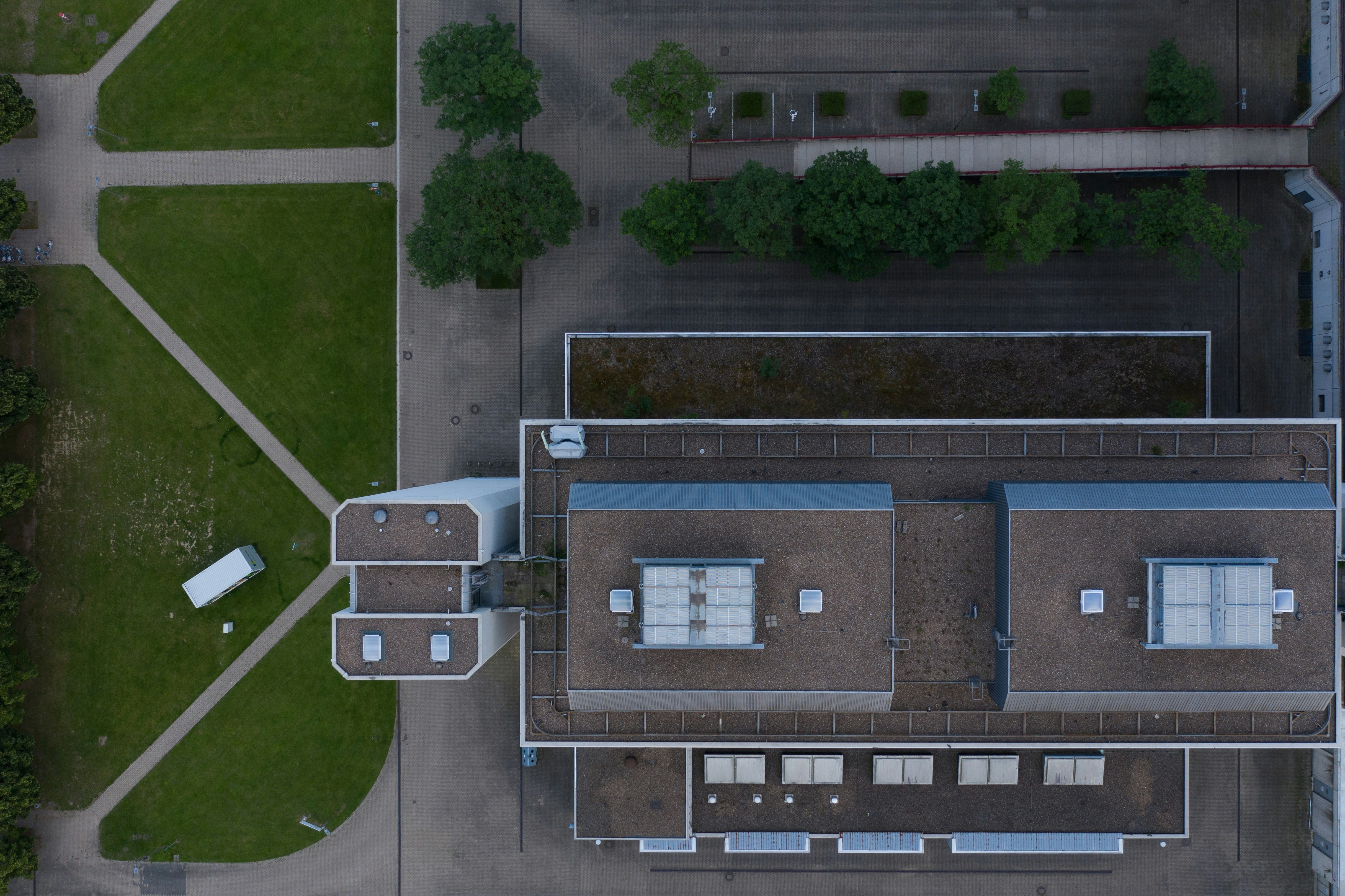 Aerial view of a symmetrical concrete building surrounded by greenery and pathways.