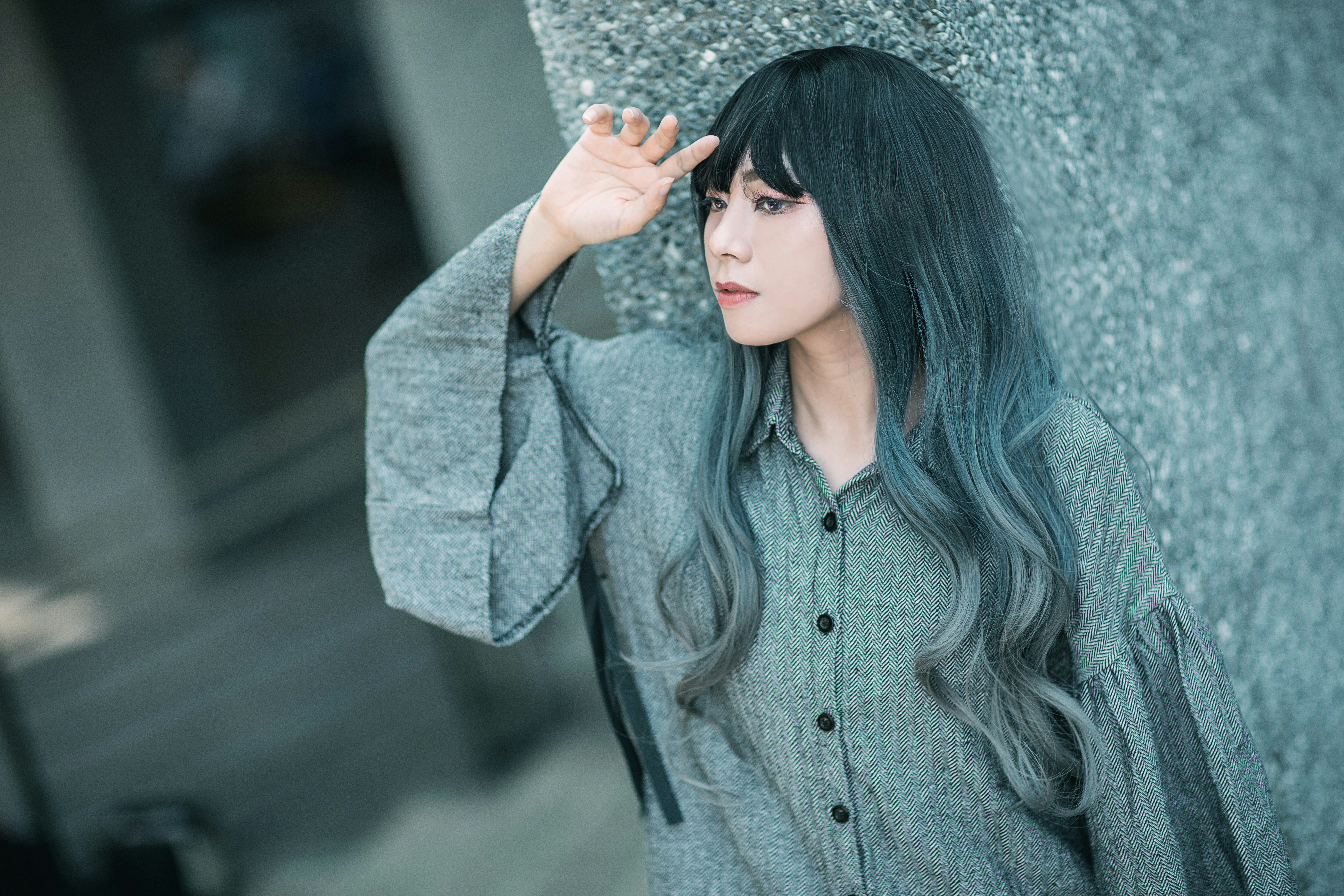 Teal-Tinted Quietude: Portrait Against a Textured Grey Wall