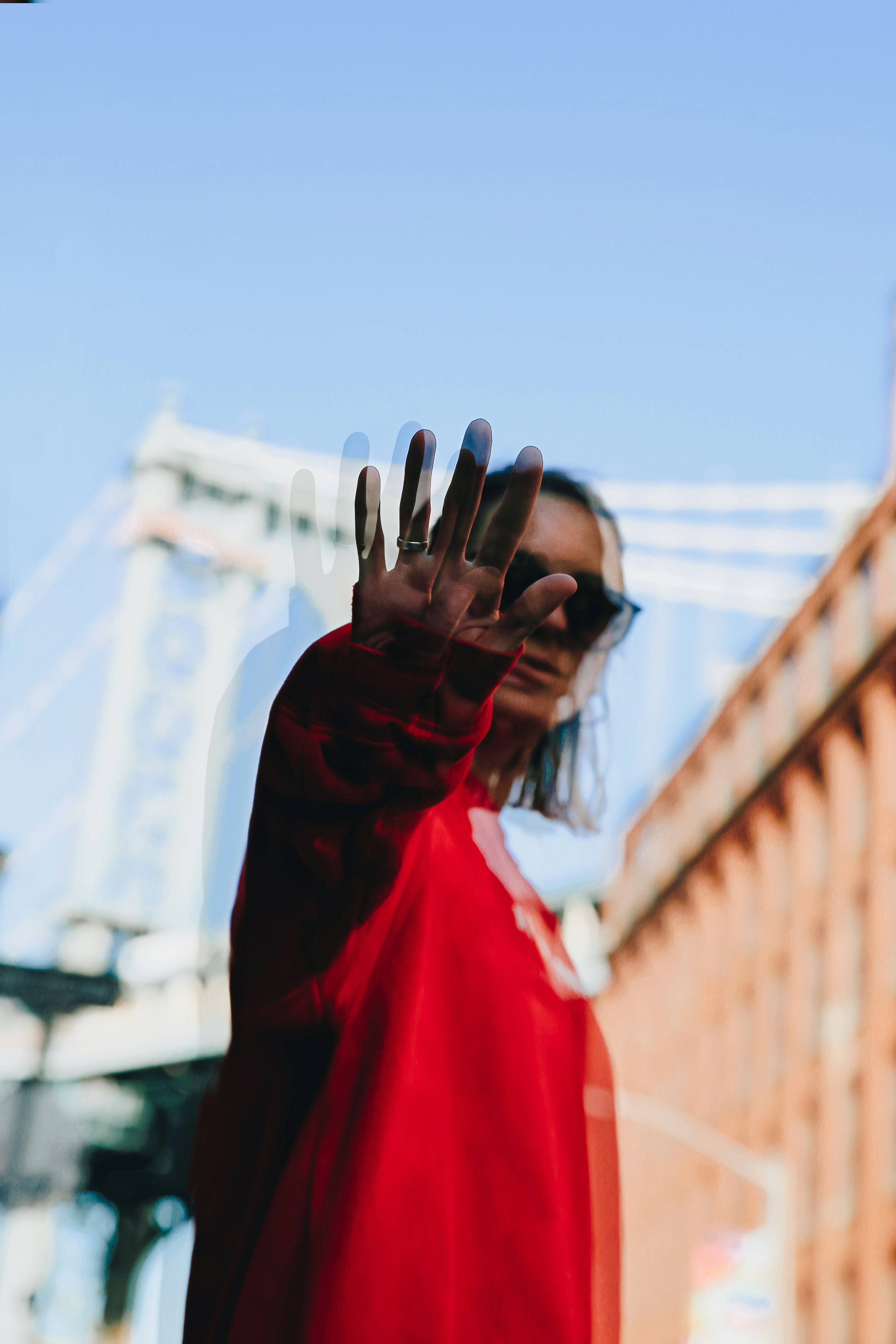 Crimson Gesture Beyond Glass: Hand Across the City Bridge