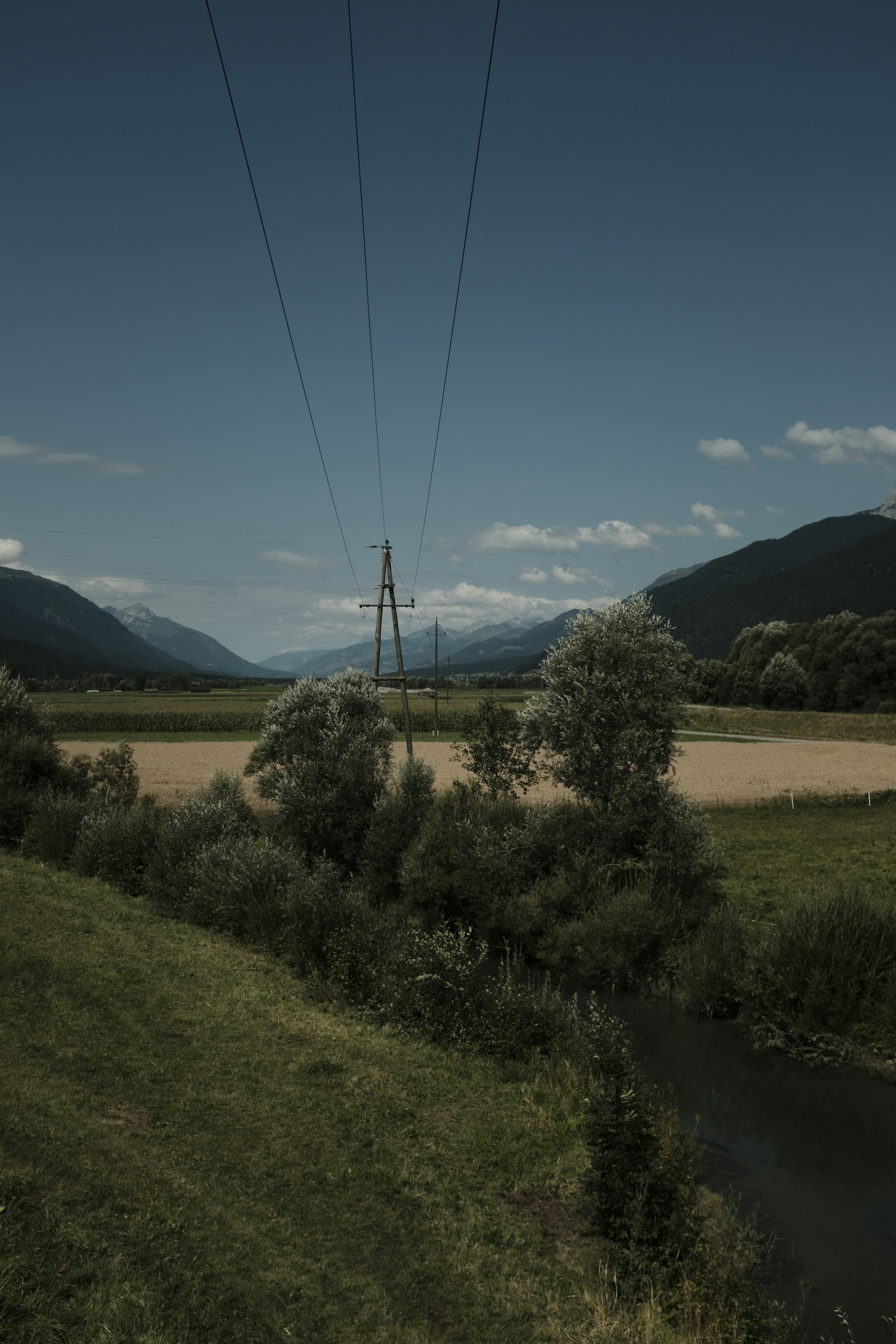 Convergence Over the Alpine Vale: A Lone Transmission Pole Framing the Valley