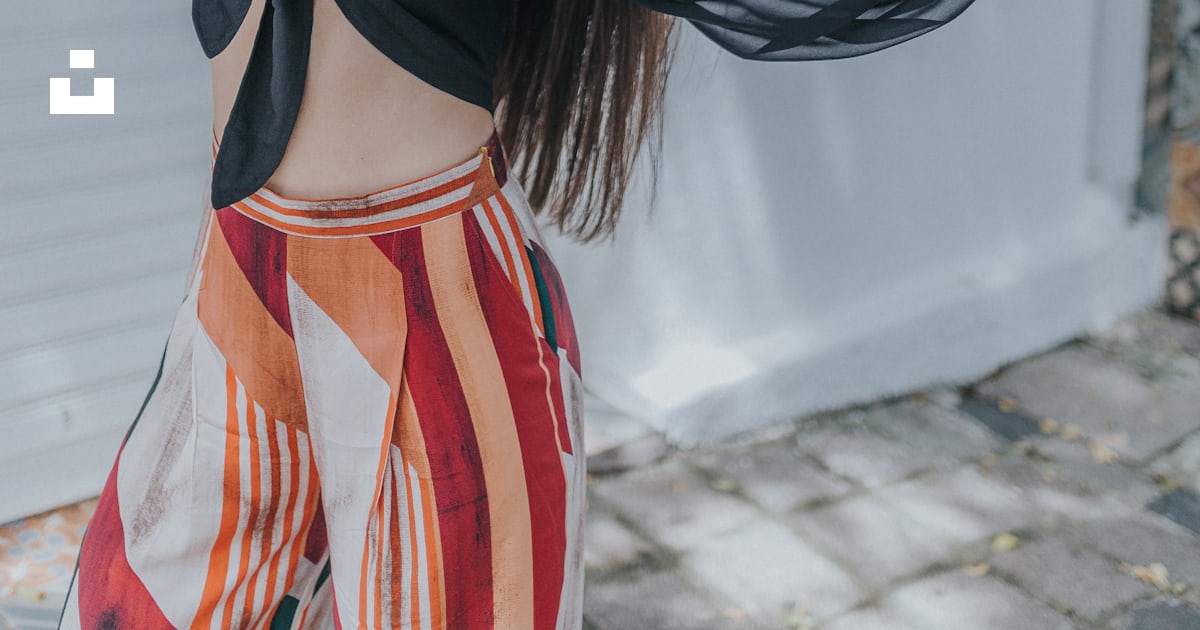 Foto Mujer Vestida De Negro Y Naranja Parada Cerca De Una Pared Blanca