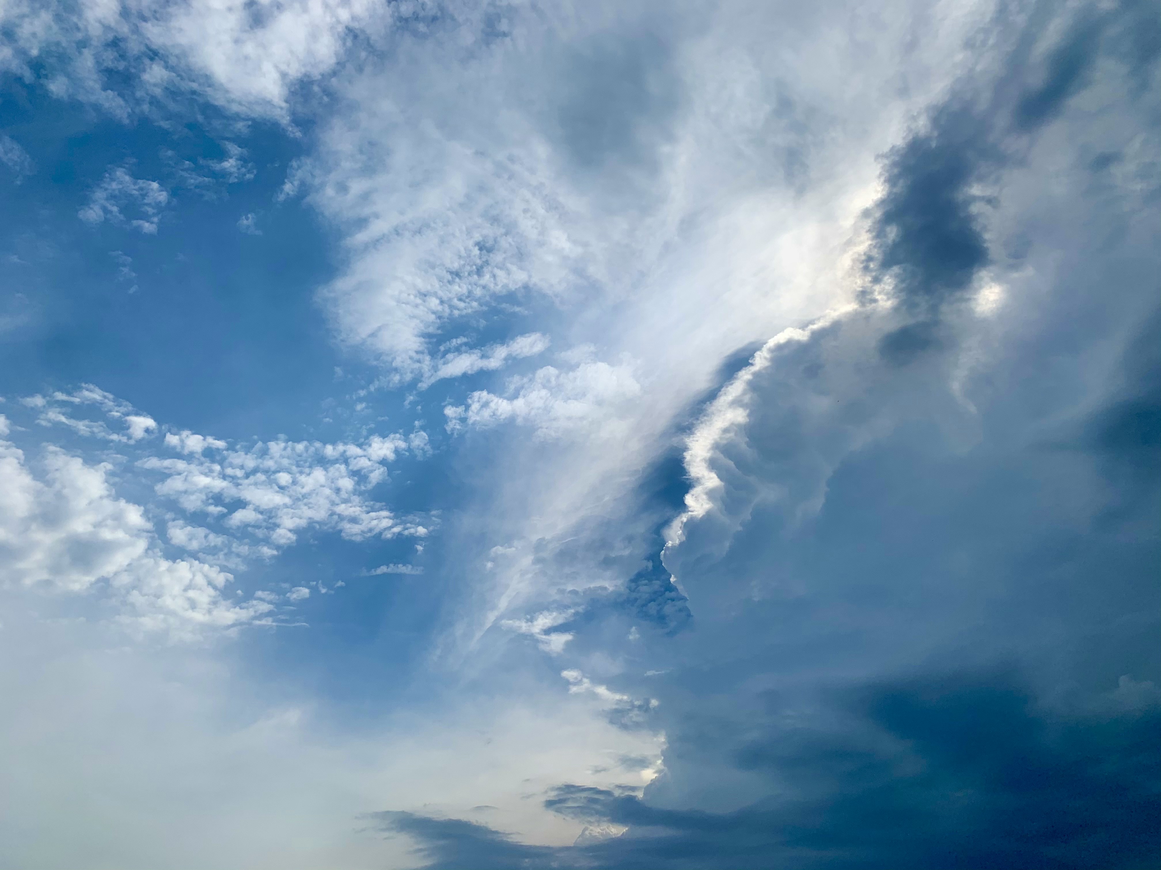 Dramatic clouds swirl against a bright blue sky, hinting at an approaching storm.