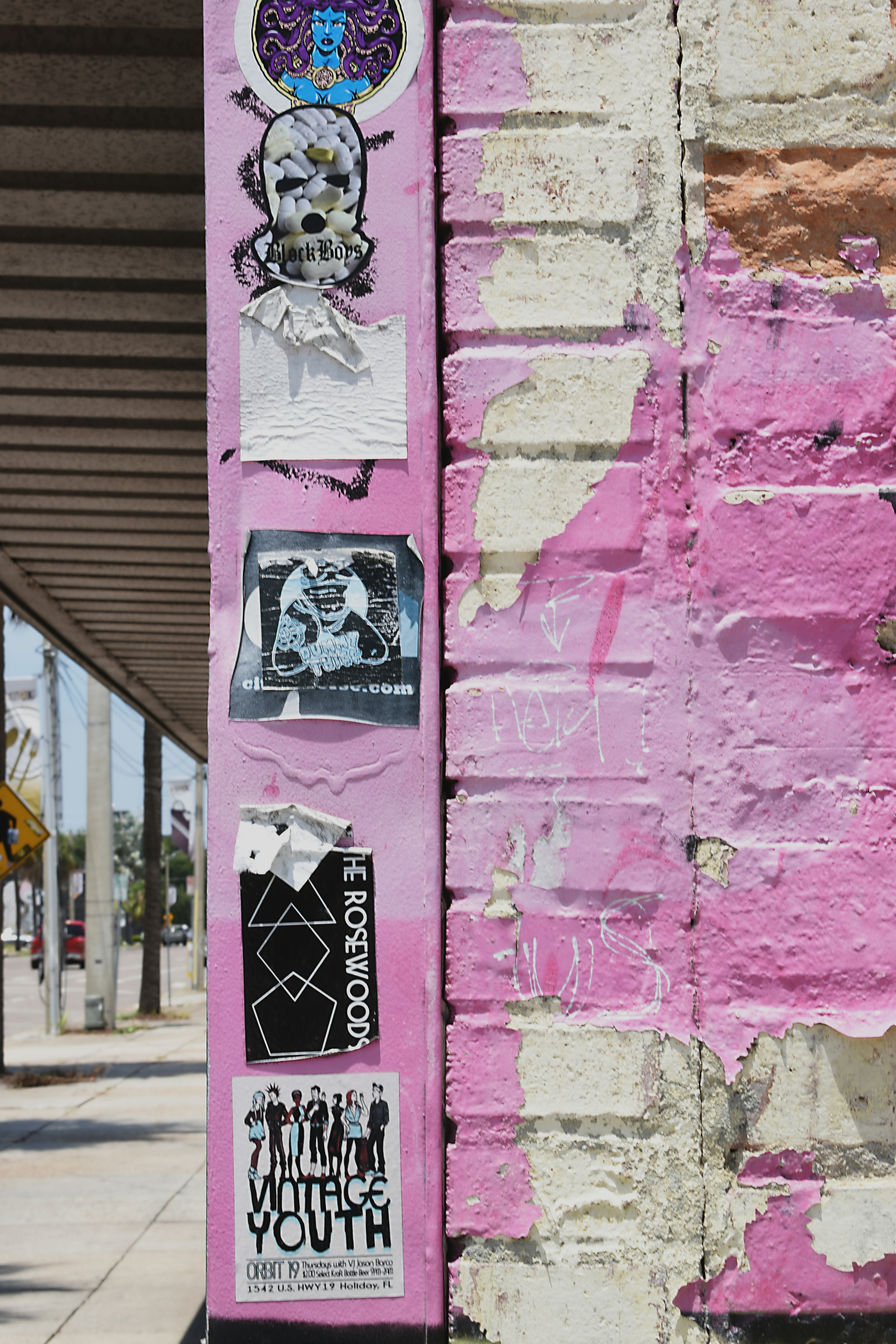 Stickered Pink Wall: A Column of Urban Paste and Painted Brick