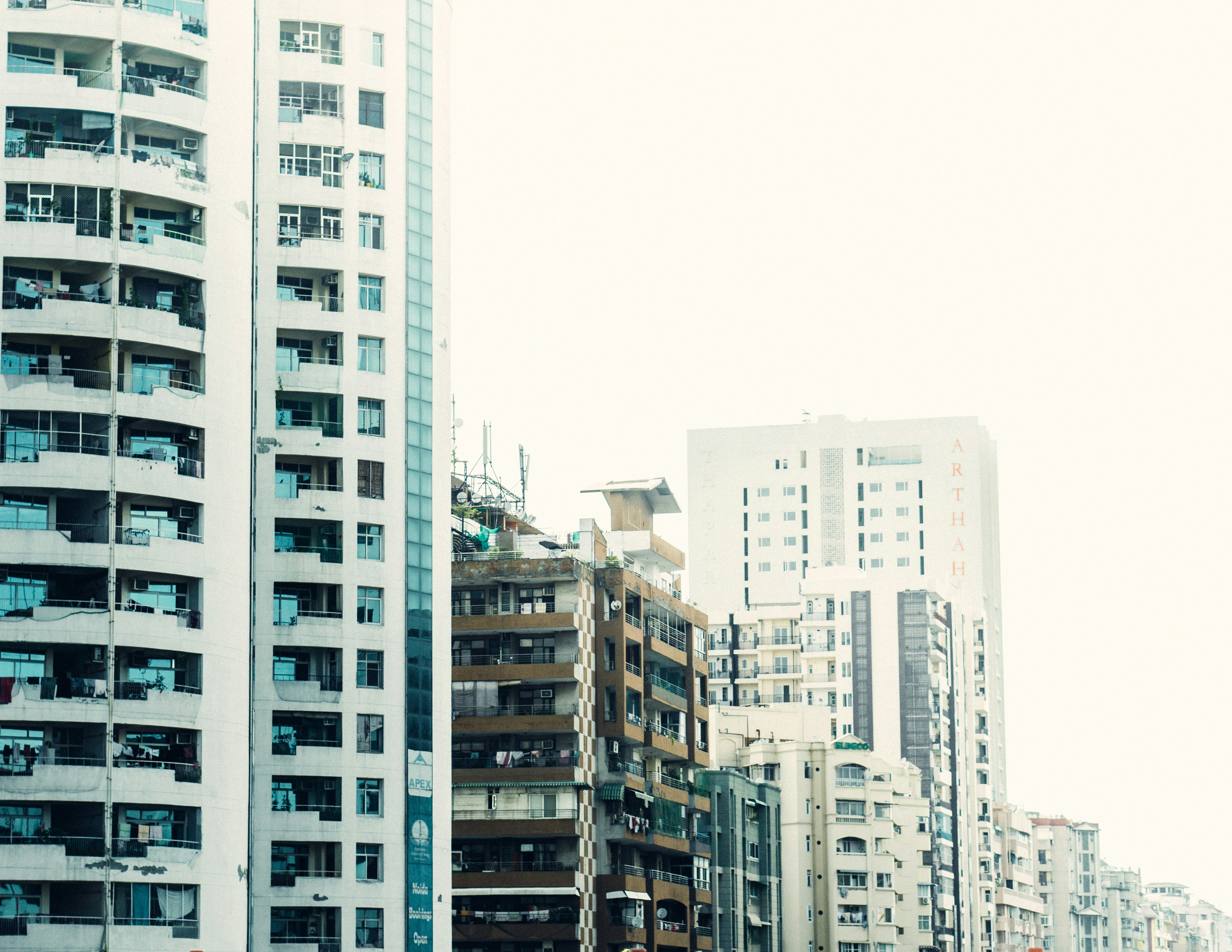 Tall apartment buildings with varied architectural styles under a bright, overcast sky.