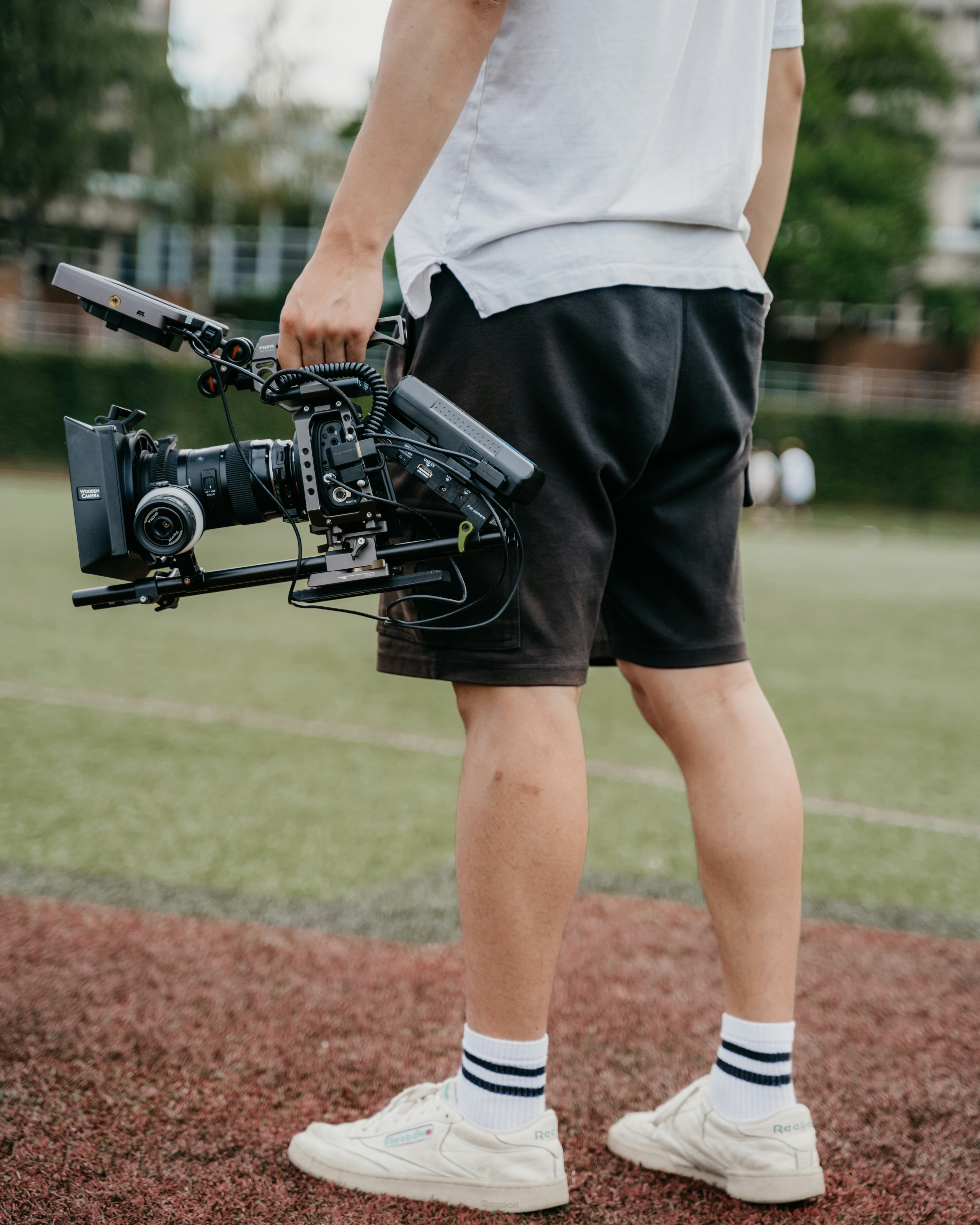 Cinematographer holding a Sony Alpha 7 III camera rig on a sports field, showcasing the gear used for dynamic filming.