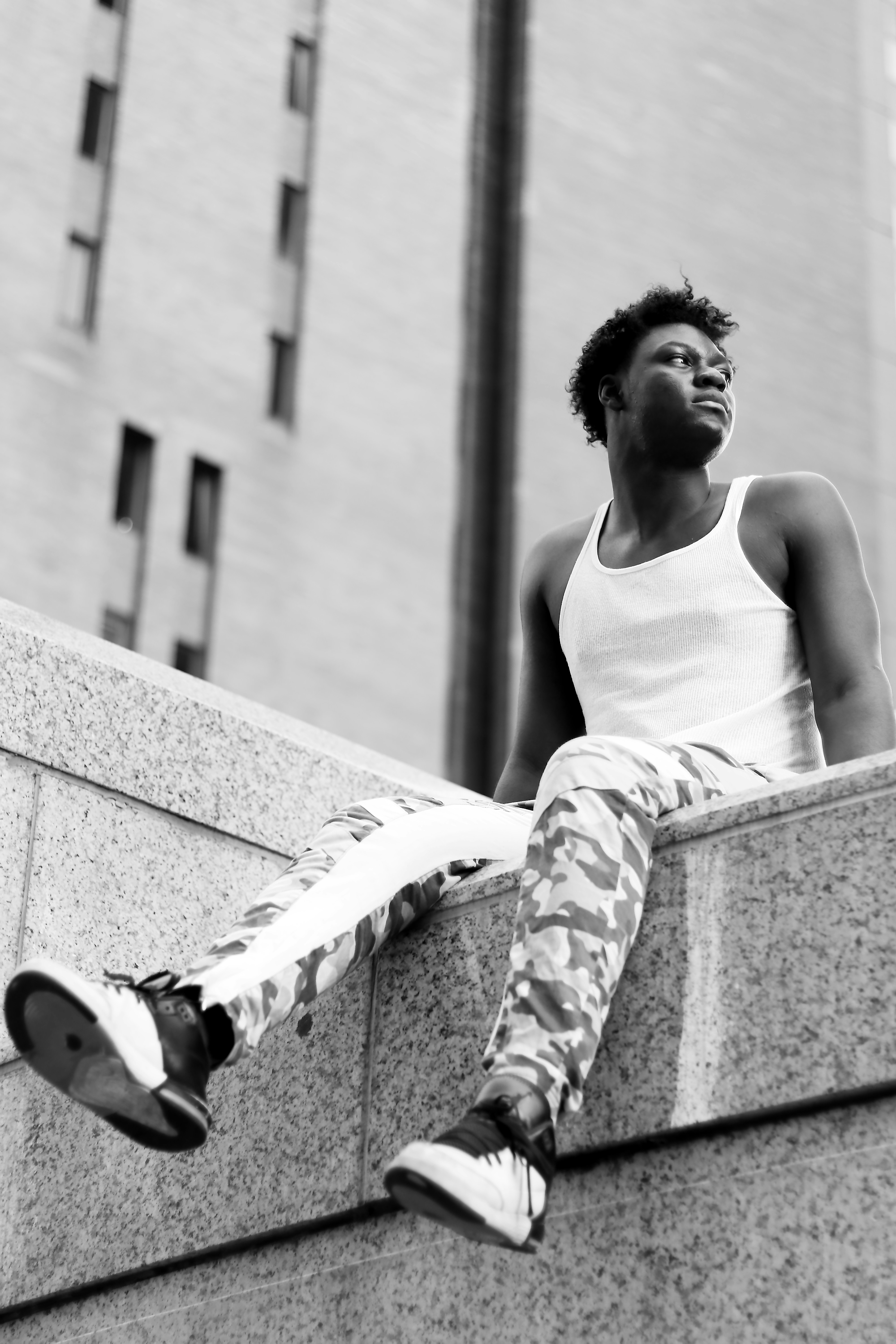 Woman in white tank top and pants sitting on concrete bench photo ...