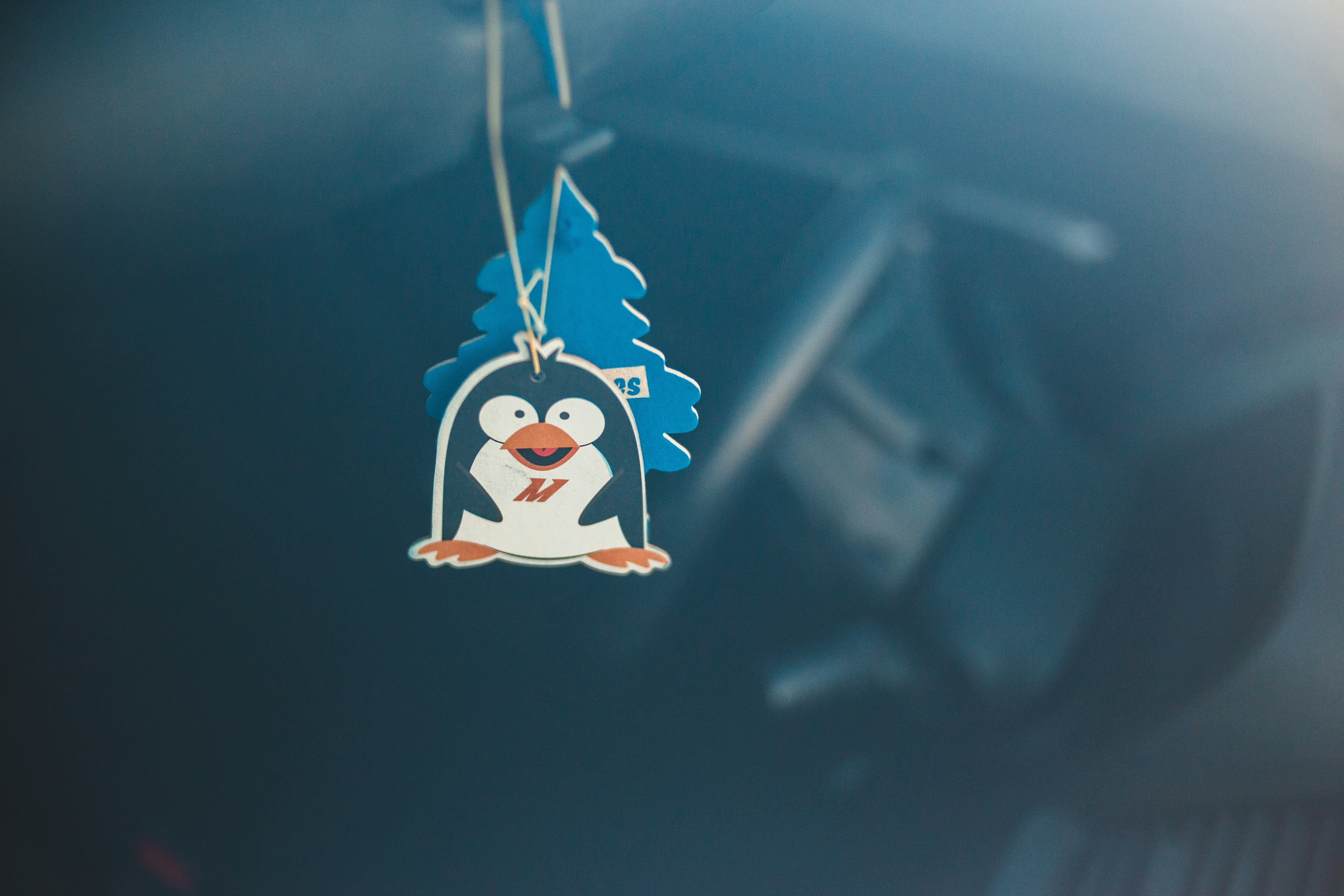 Blue-Tinted Stillness: A Penguin Air Freshener in a Car Cabin