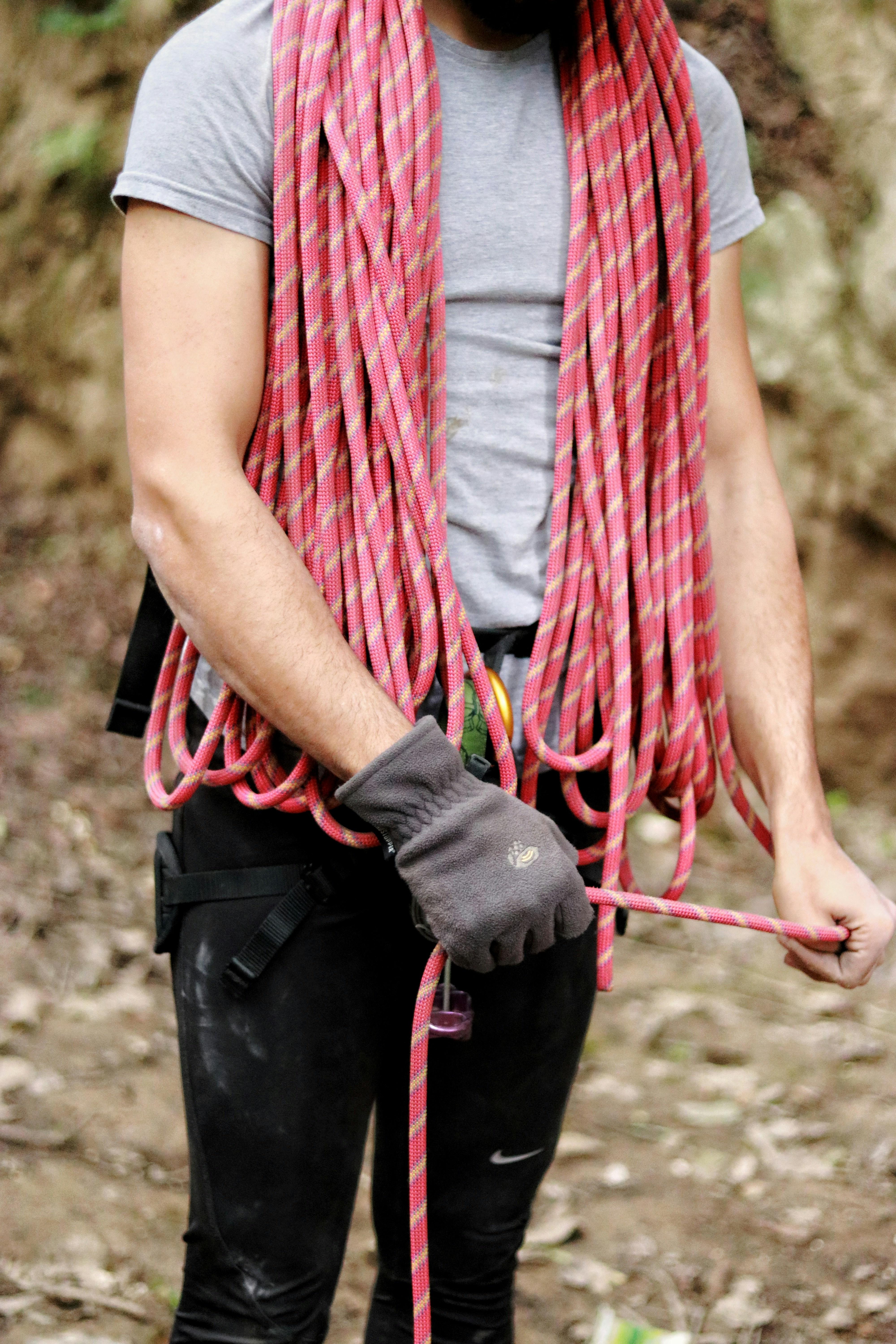 Crimson Rope Symmetry: Gloved Hands Steady a Climber's Coil Against Rugged Terrain