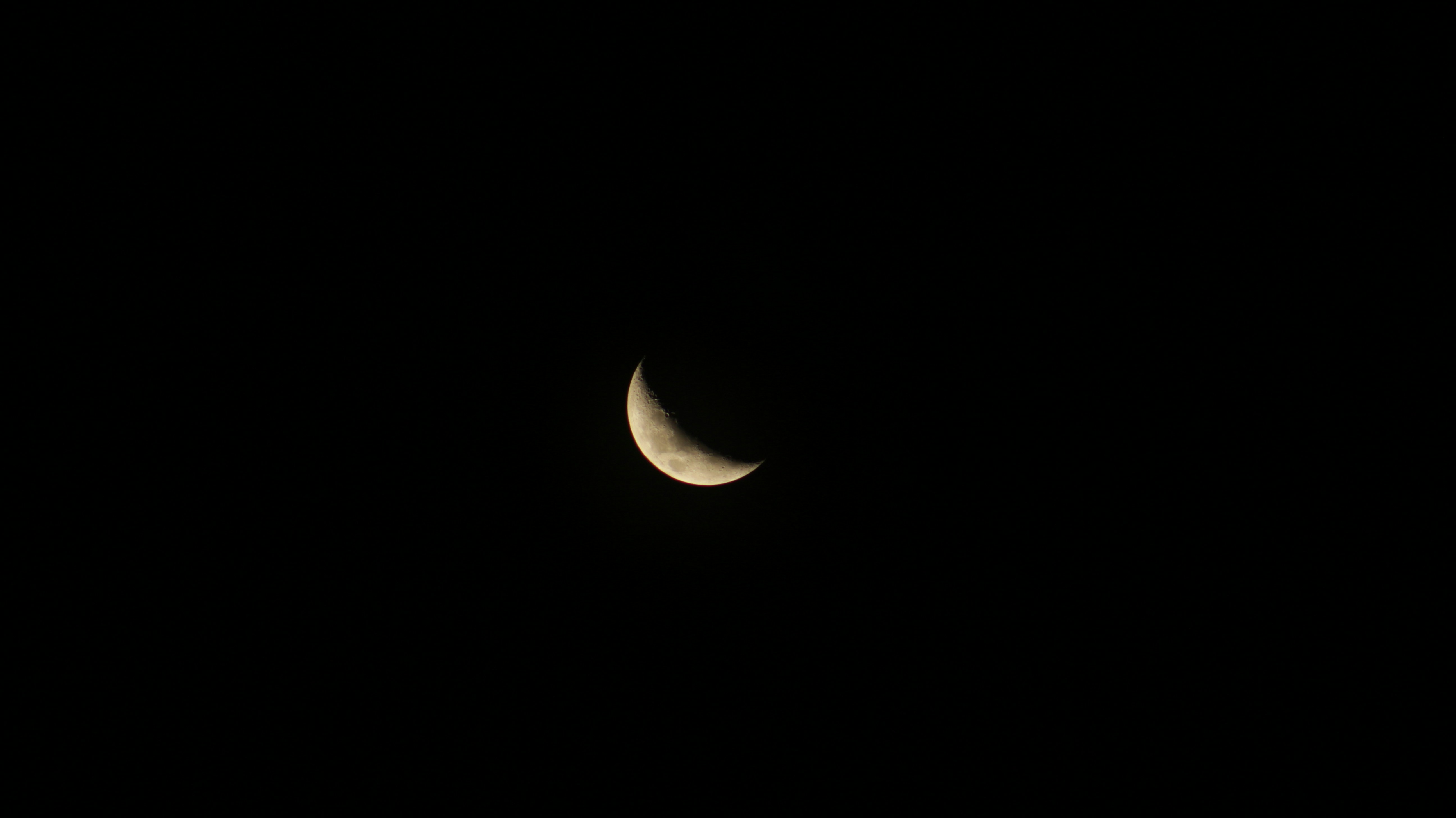 Crescent moon glowing softly against a stark black sky.