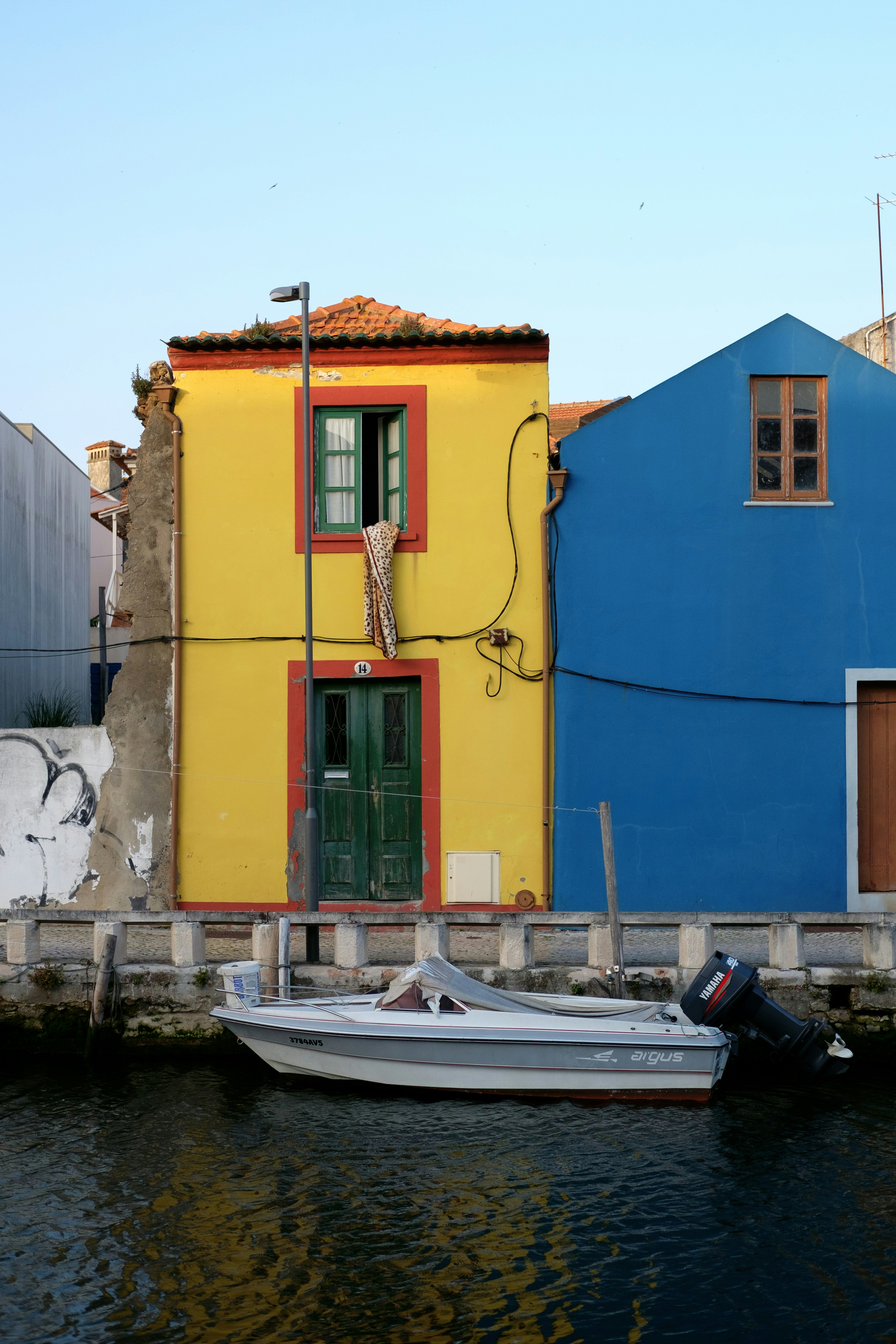 Vivid Canal Facade: A Yellow House Next to a Blue Wall by the Dock