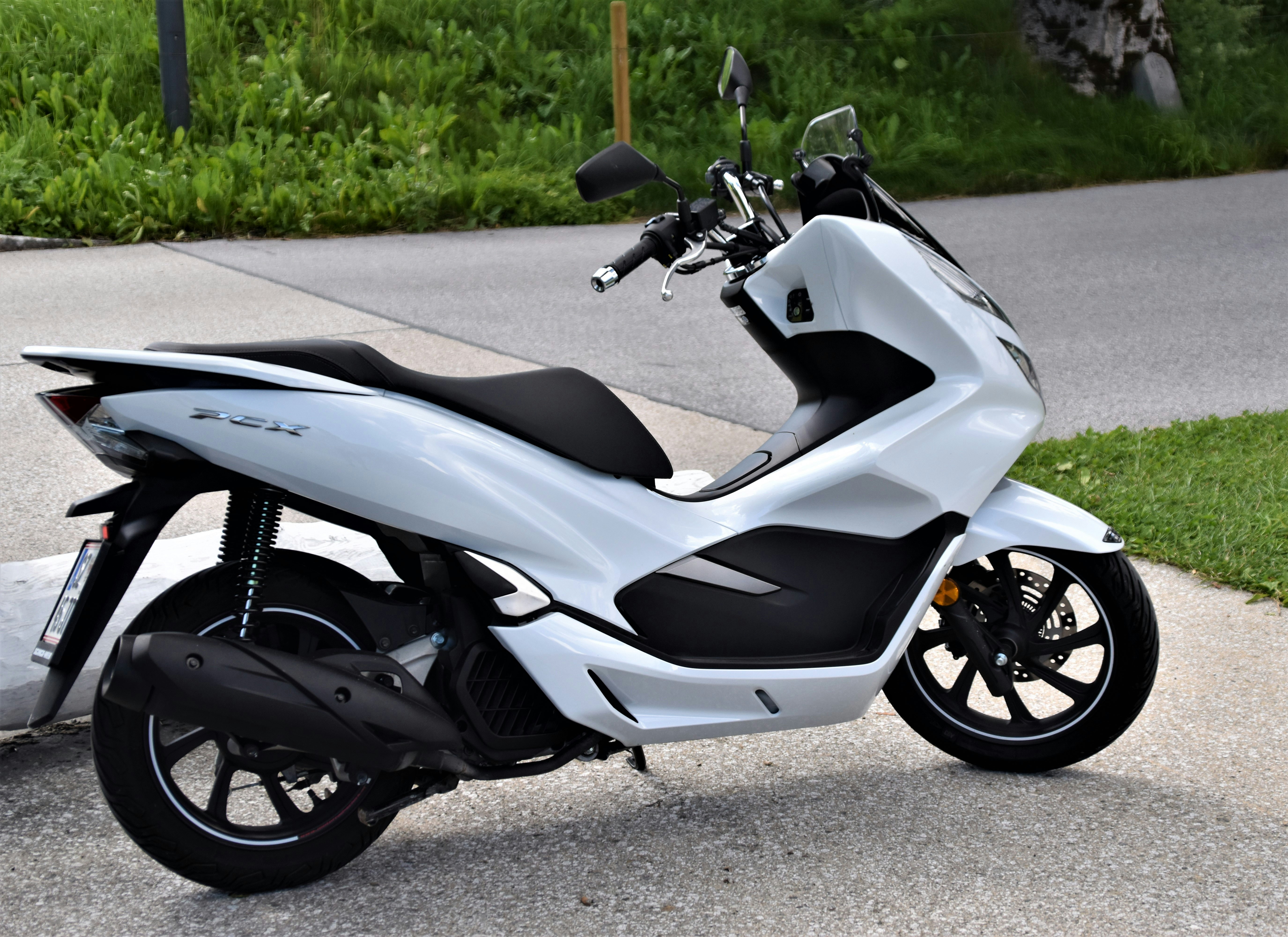 A white motor scooter is standing and waiting for his biker