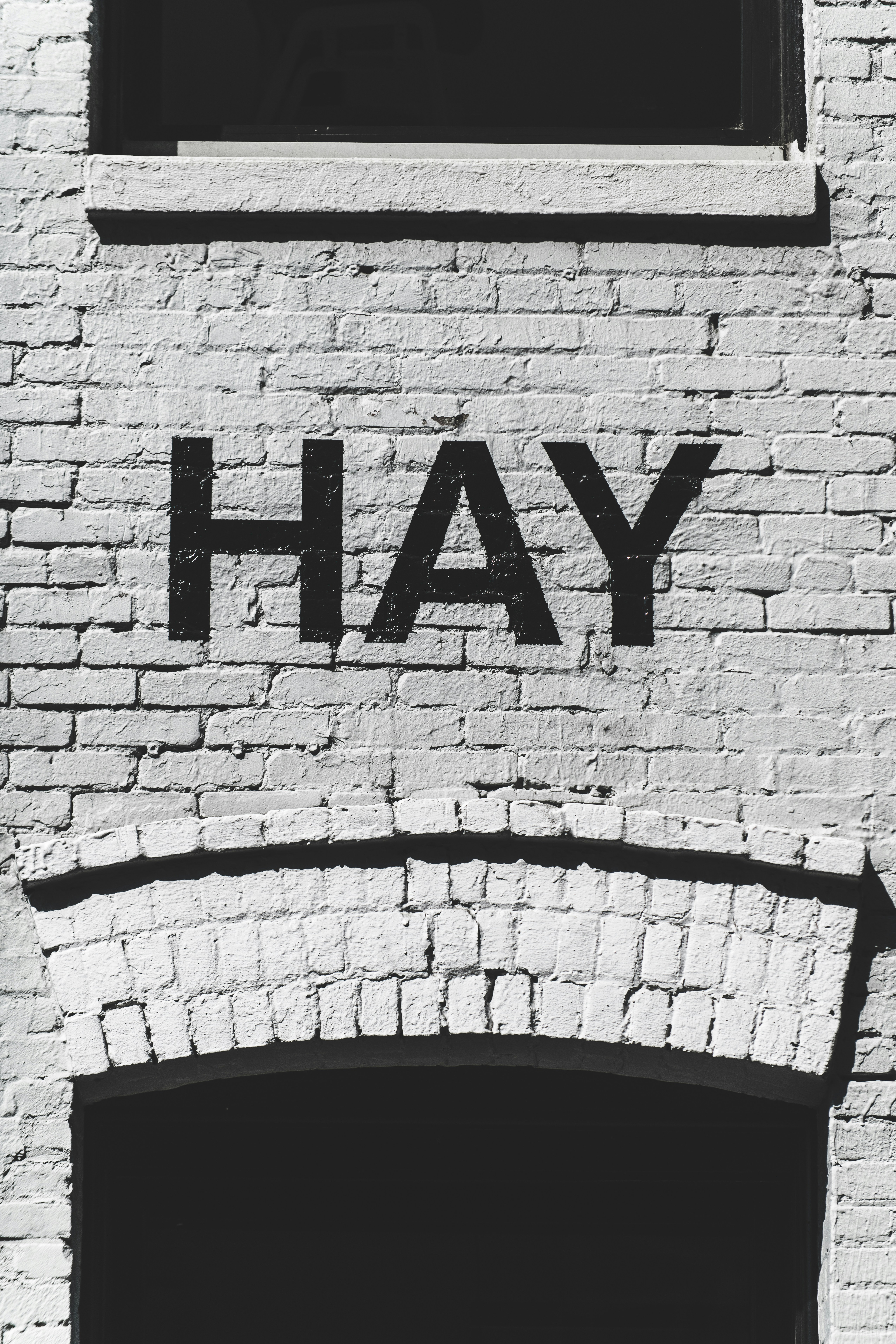 A black and white photo of a brick building with the word hay painted ...