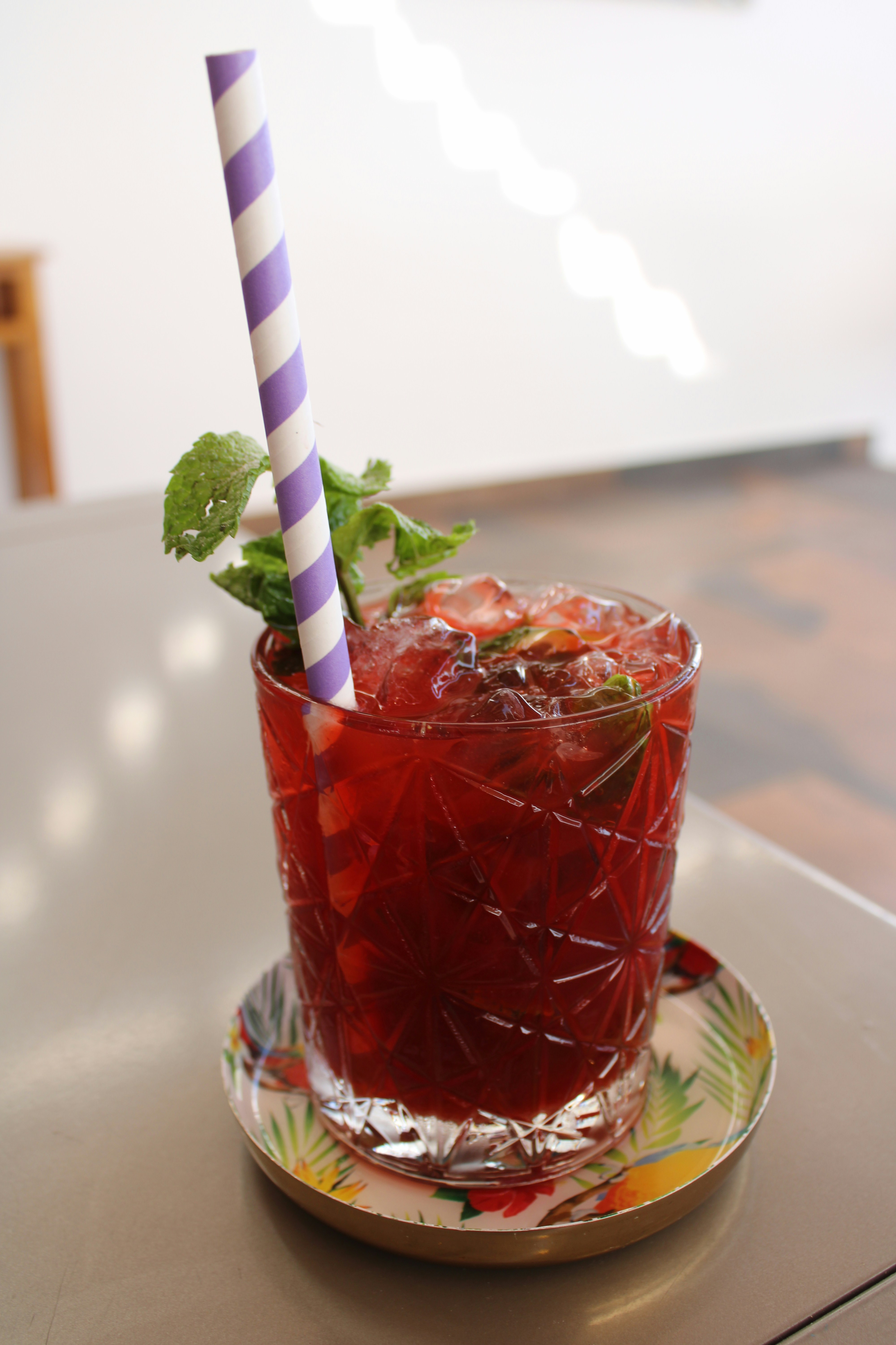 Crimson Reflections: A Mint-Leaf Cocktail Framed by Faceted Glass