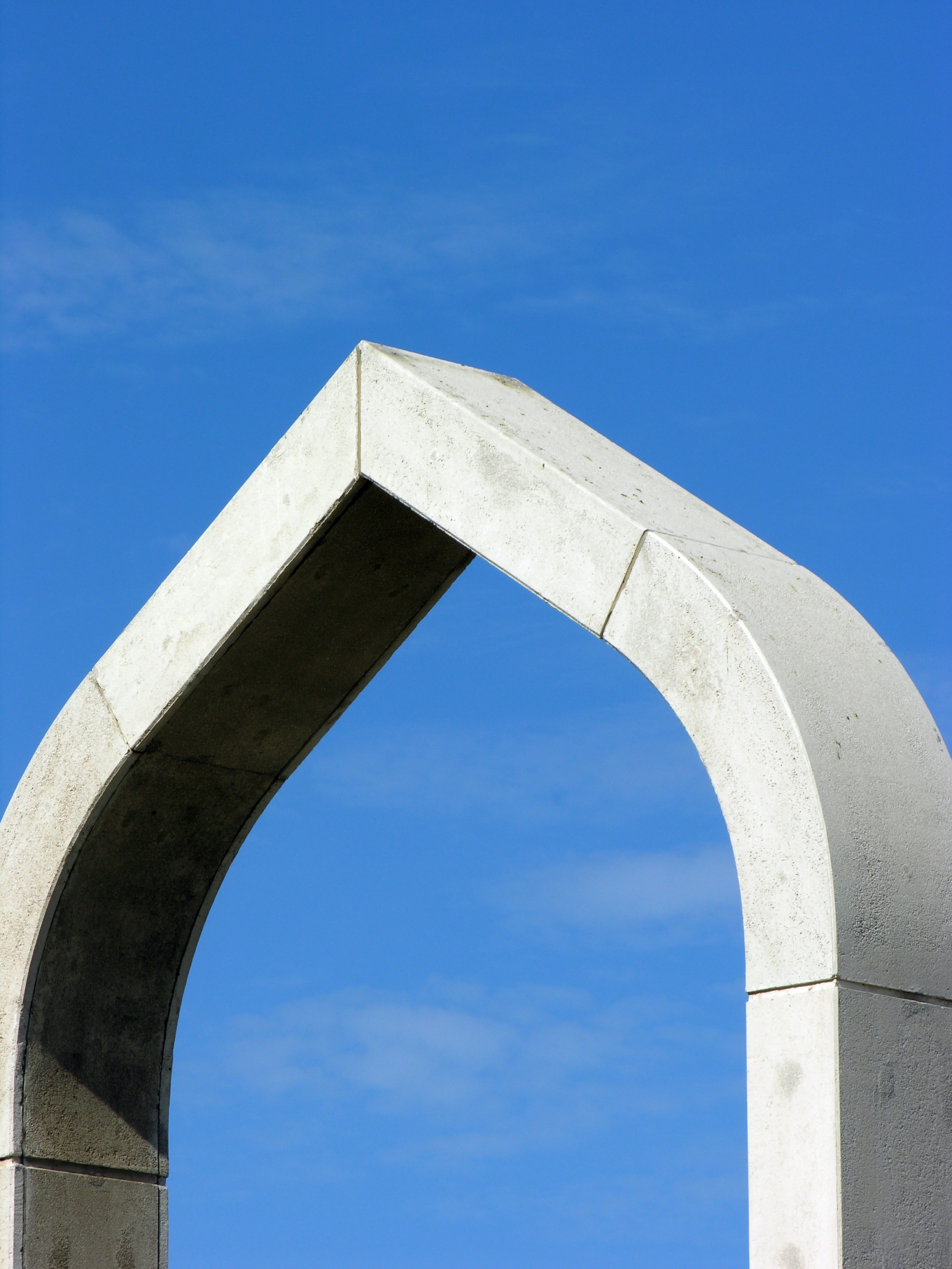 Concrete archway reaching towards the sky, framed by a vibrant blue backdrop. The structure's clean lines and modern design stand out prominently.