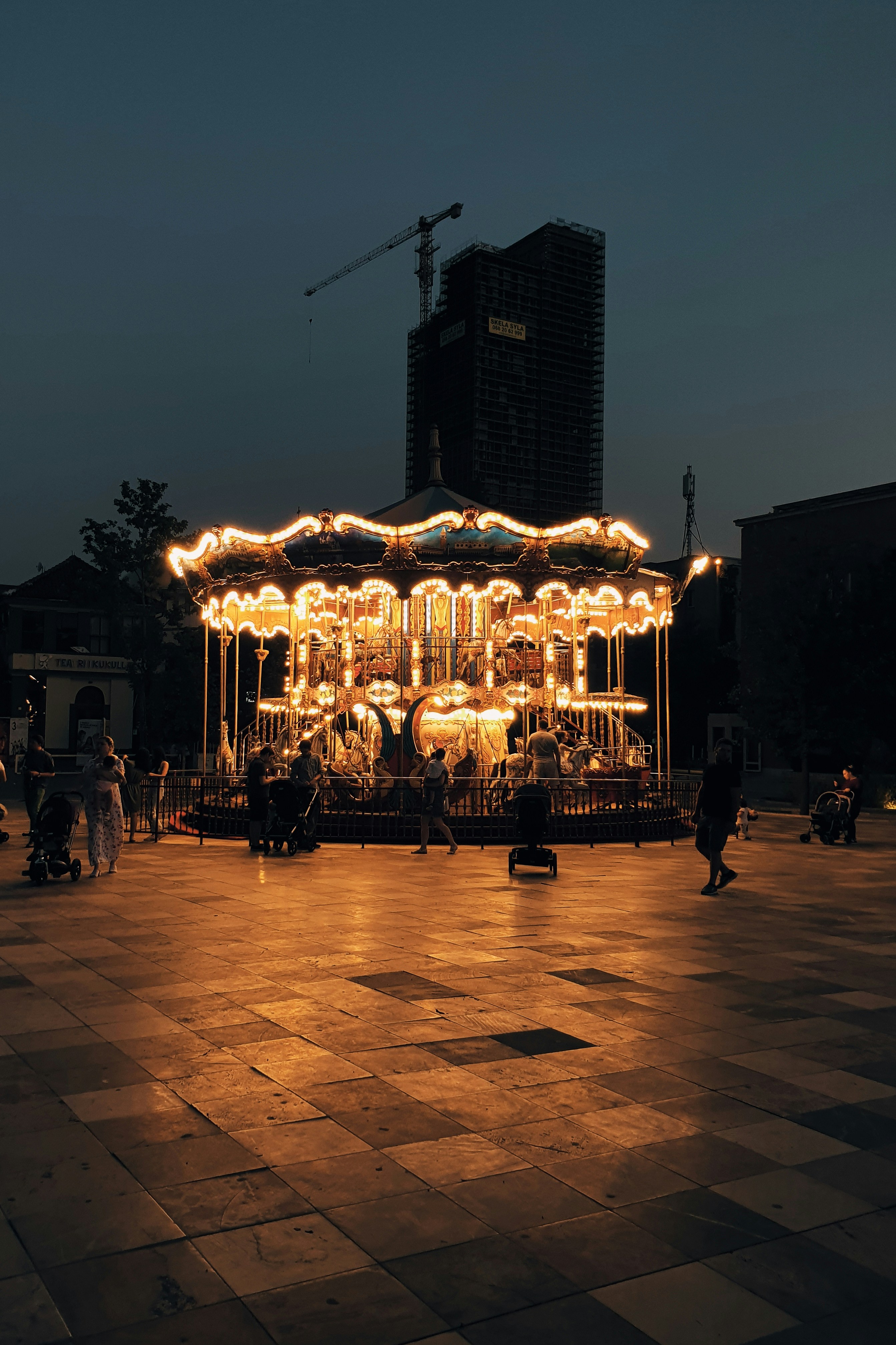 Night Carousel Radiance in a City Square Against a Rising Skyline