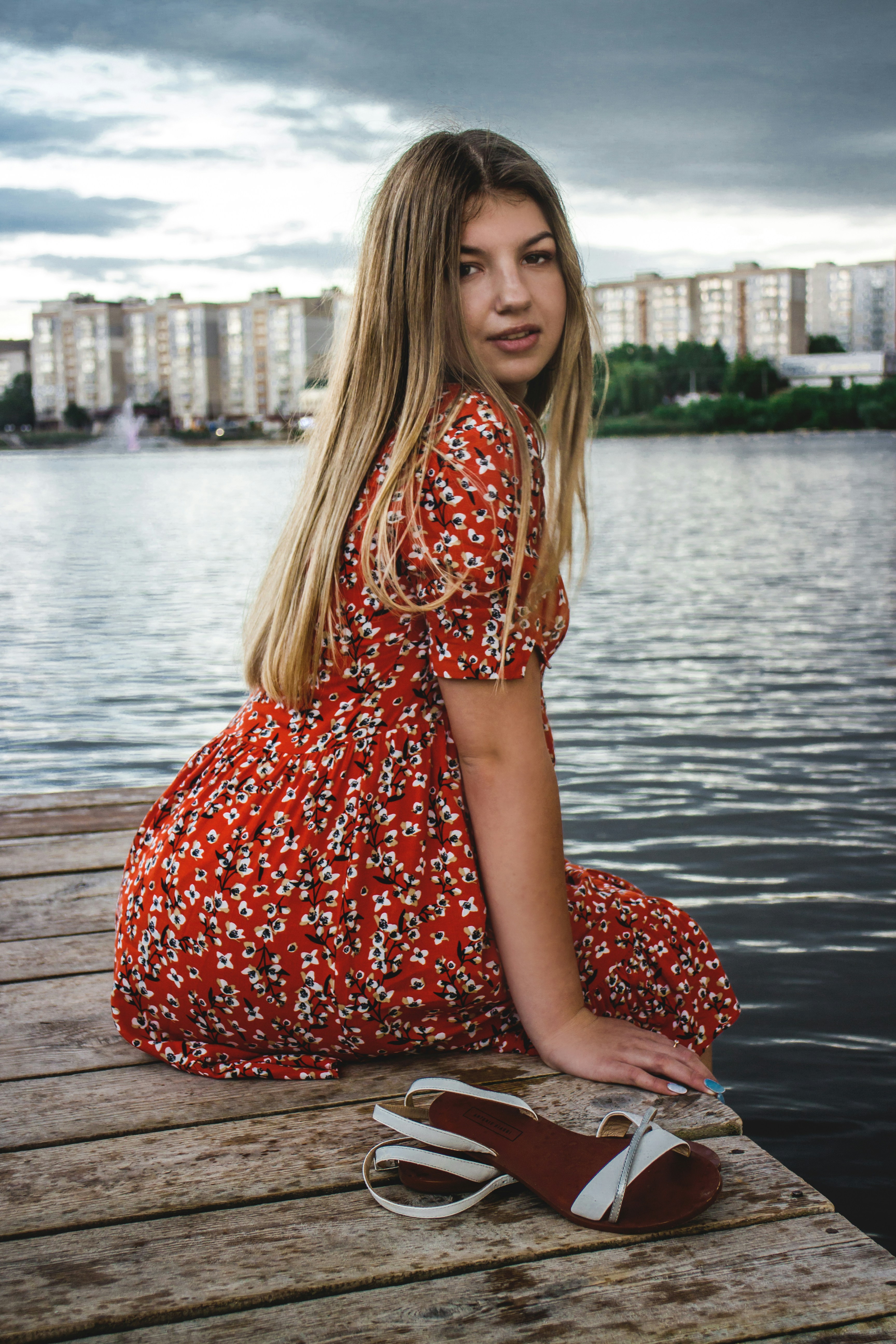 Red Floral Reverie by the Lake: Portrait on a Dock with a City Backdrop