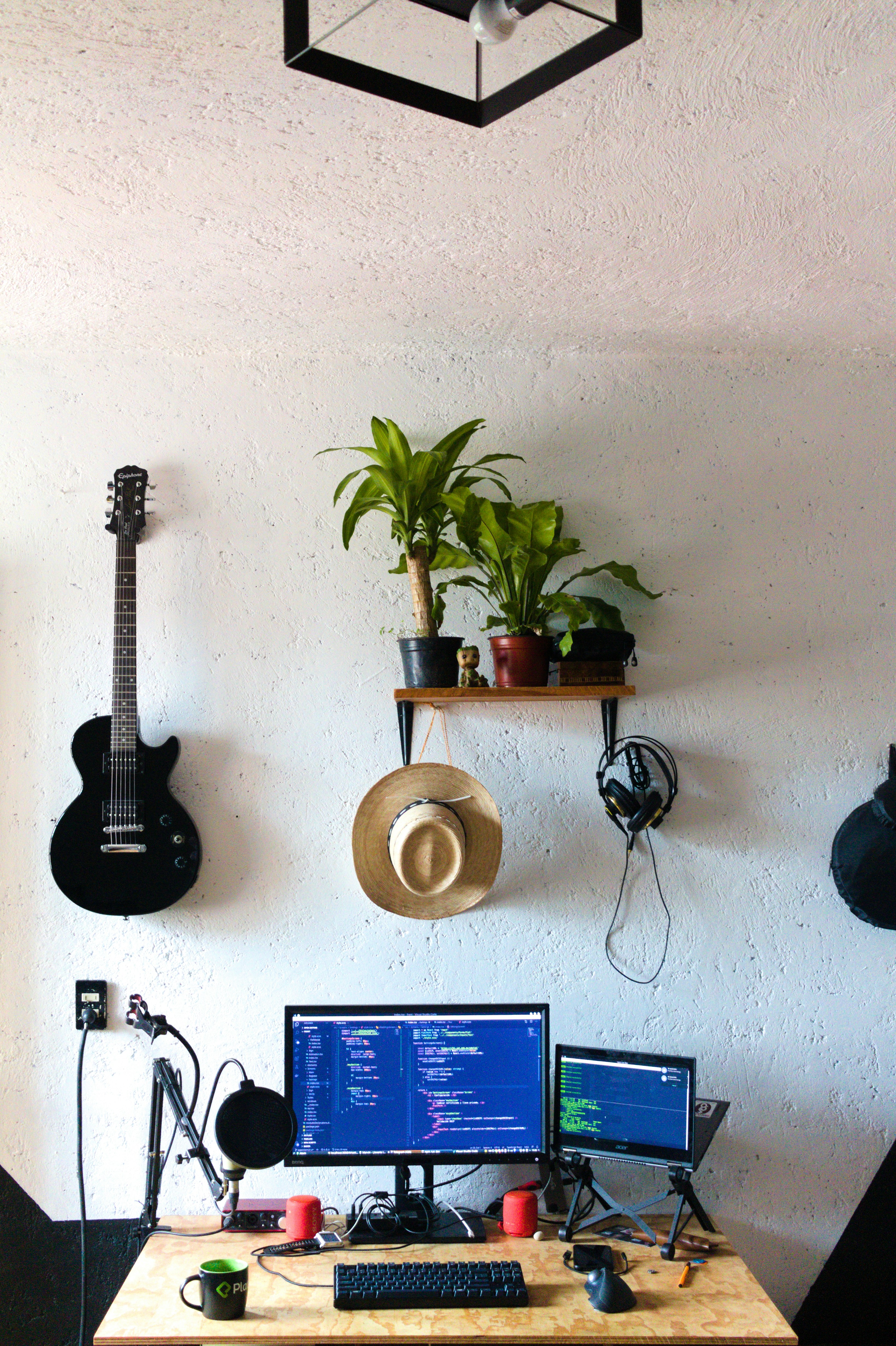 Stylish workspace featuring dual monitors, a guitar, and vibrant plants, showcasing a blend of technology and nature.