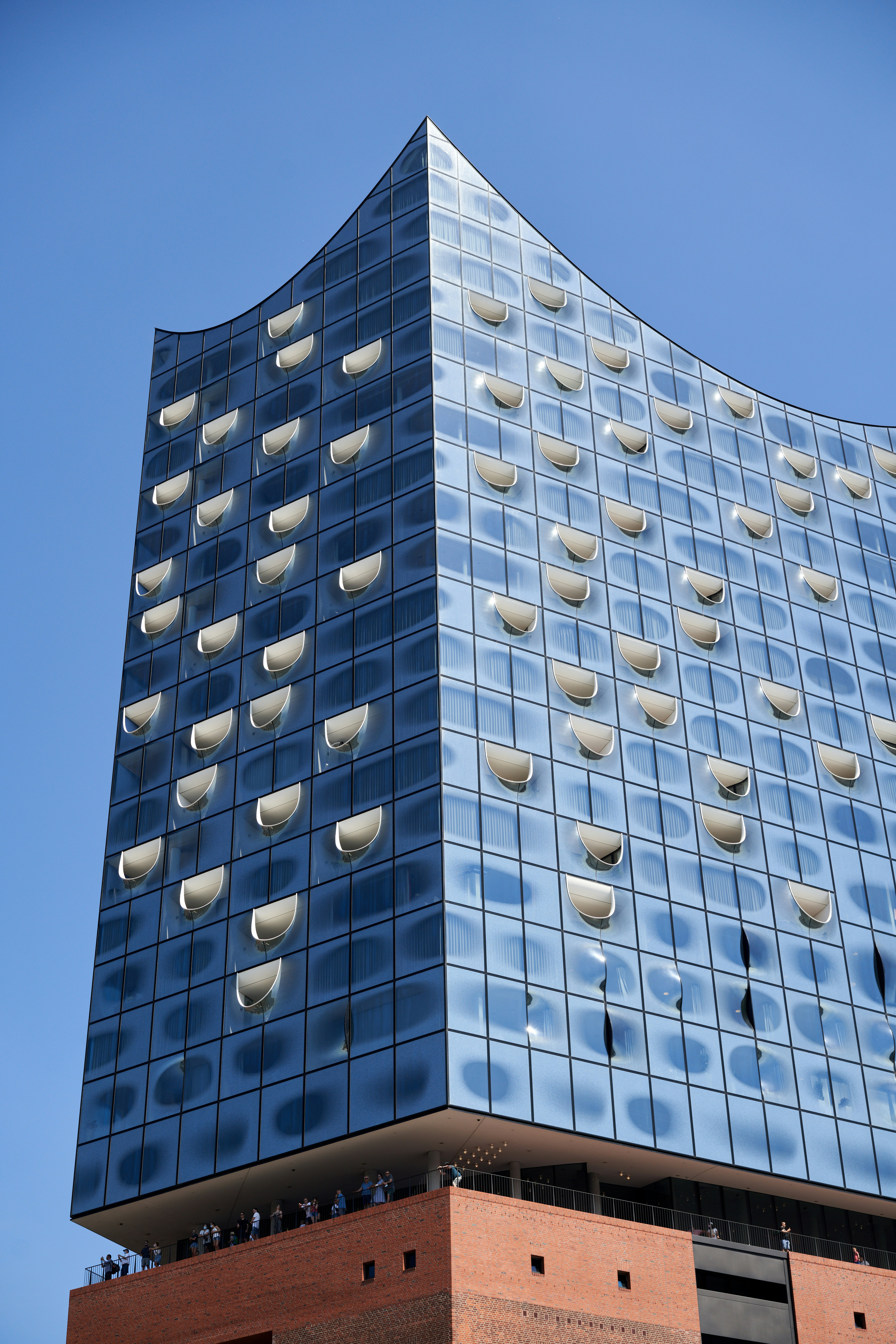 Apex in Blue: The Curved Glass Tower Over Brick Base