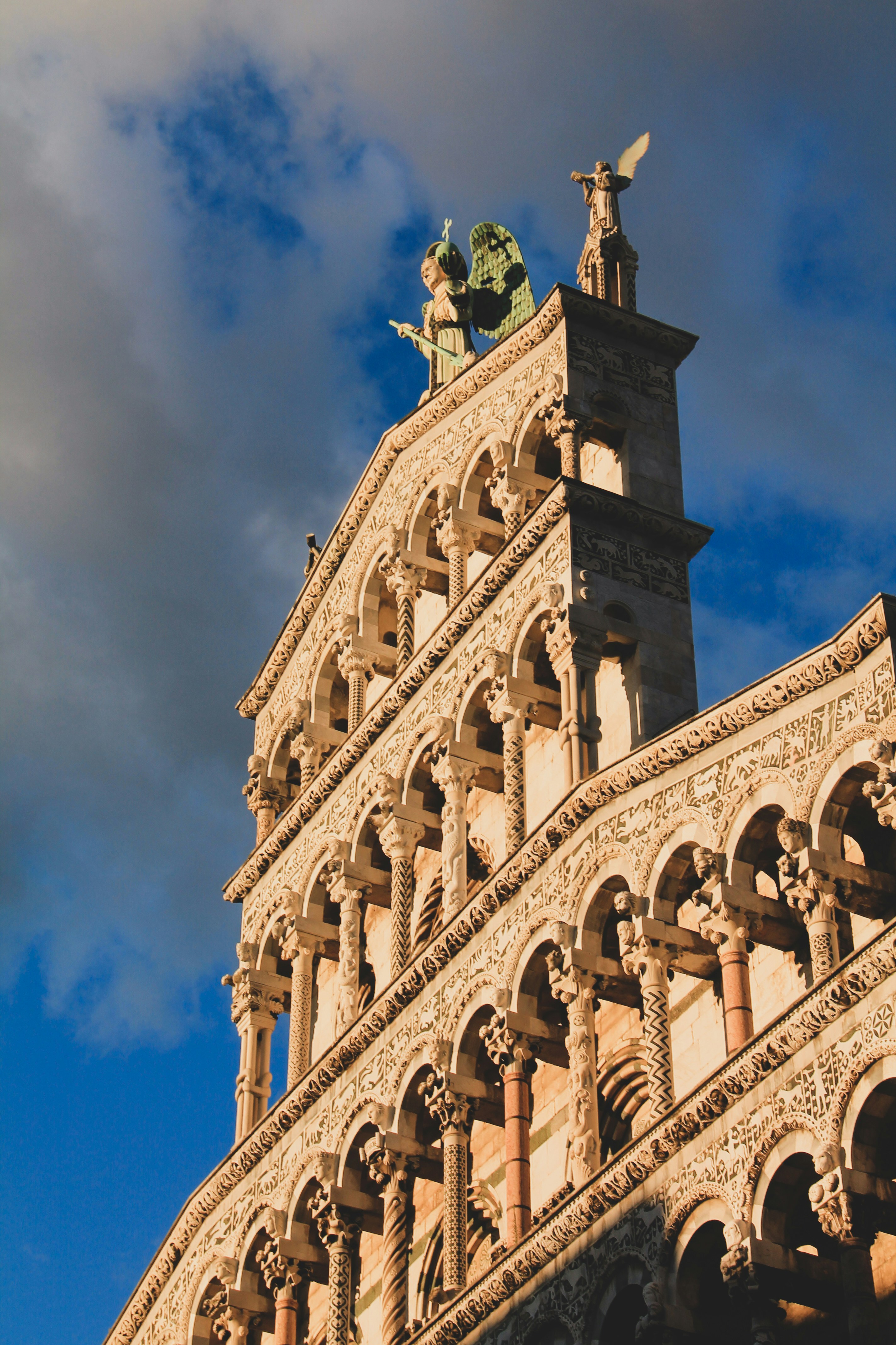Intricate facade of a historic building illuminated by golden sunlight against a dramatic sky.