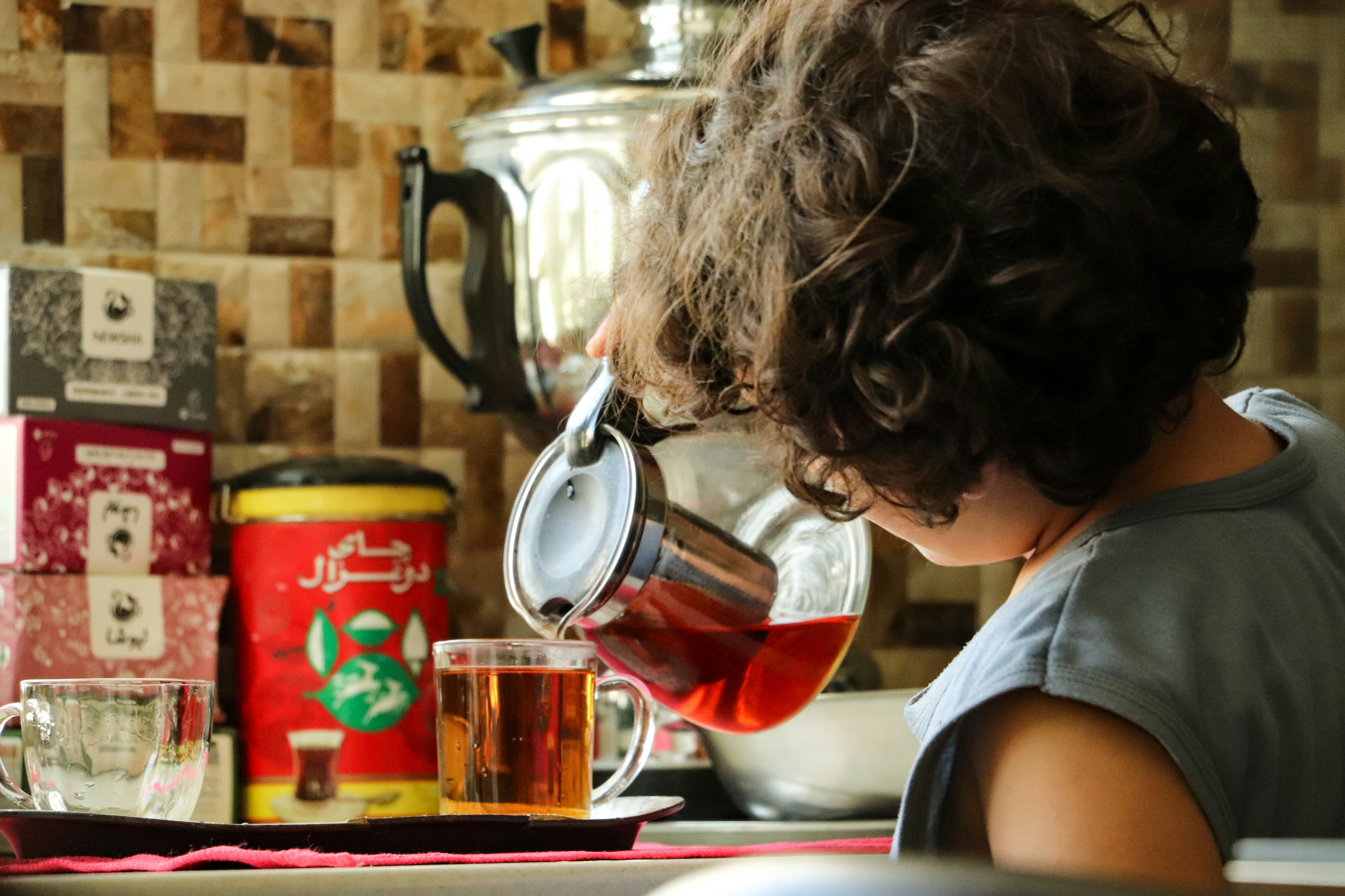 Curious Pour: A Child Balances Tea in a Cozy Kitchen