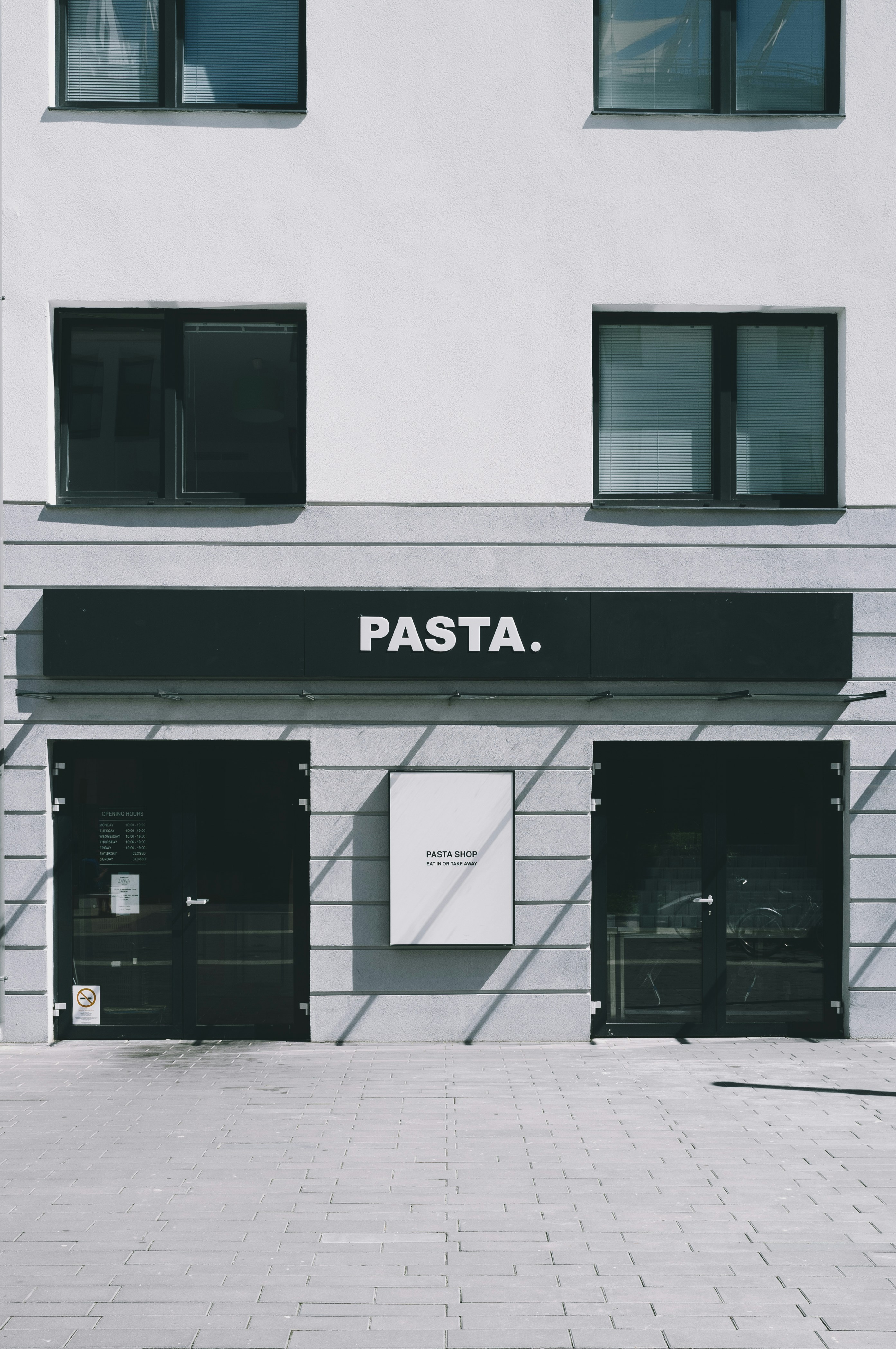 Chic restaurant exterior showcasing the word 'PASTA.' against a minimalist facade with geometric shadows.