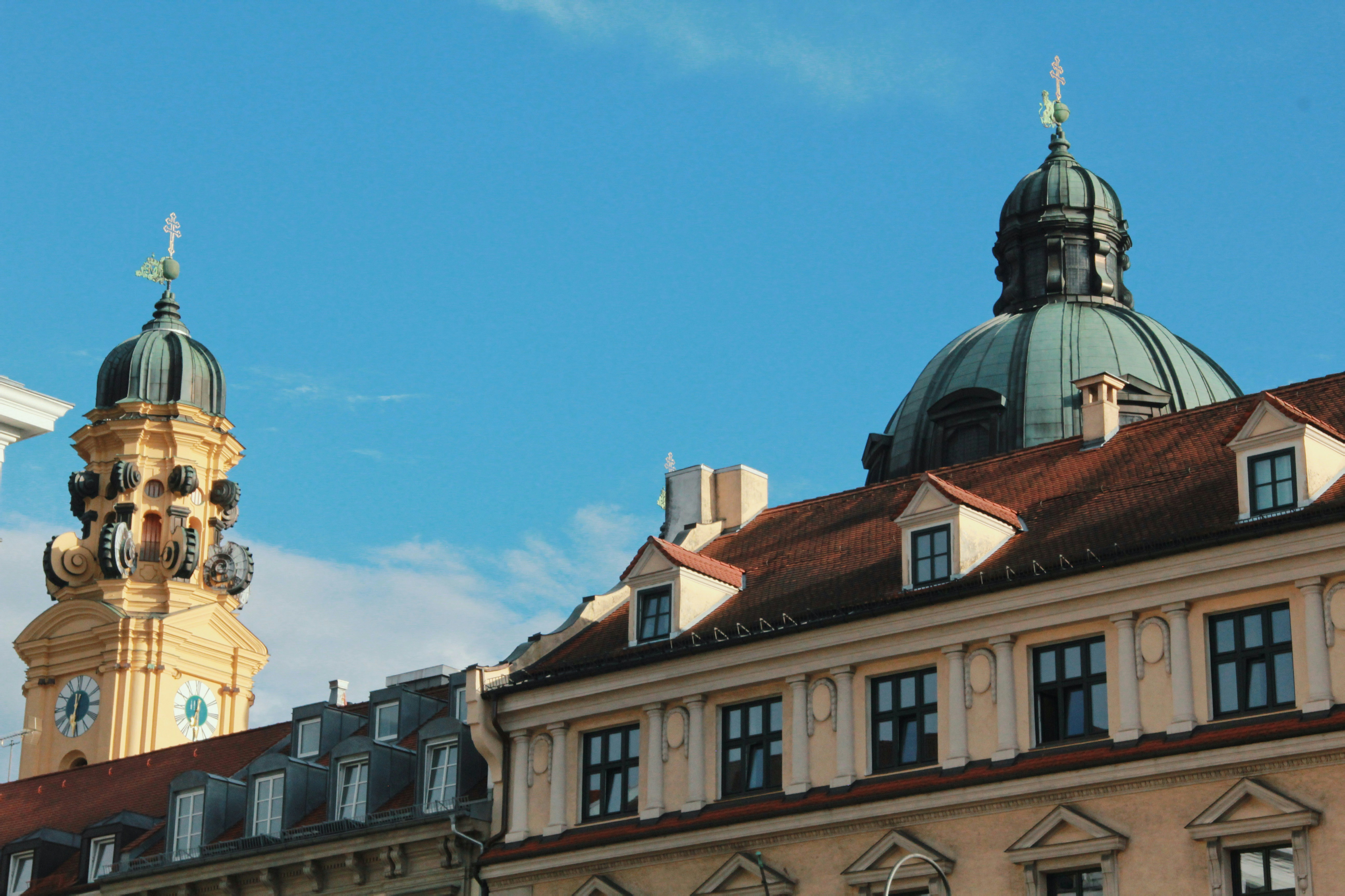 Historic Munich rooftops with intricate domes set against a vivid blue sky.