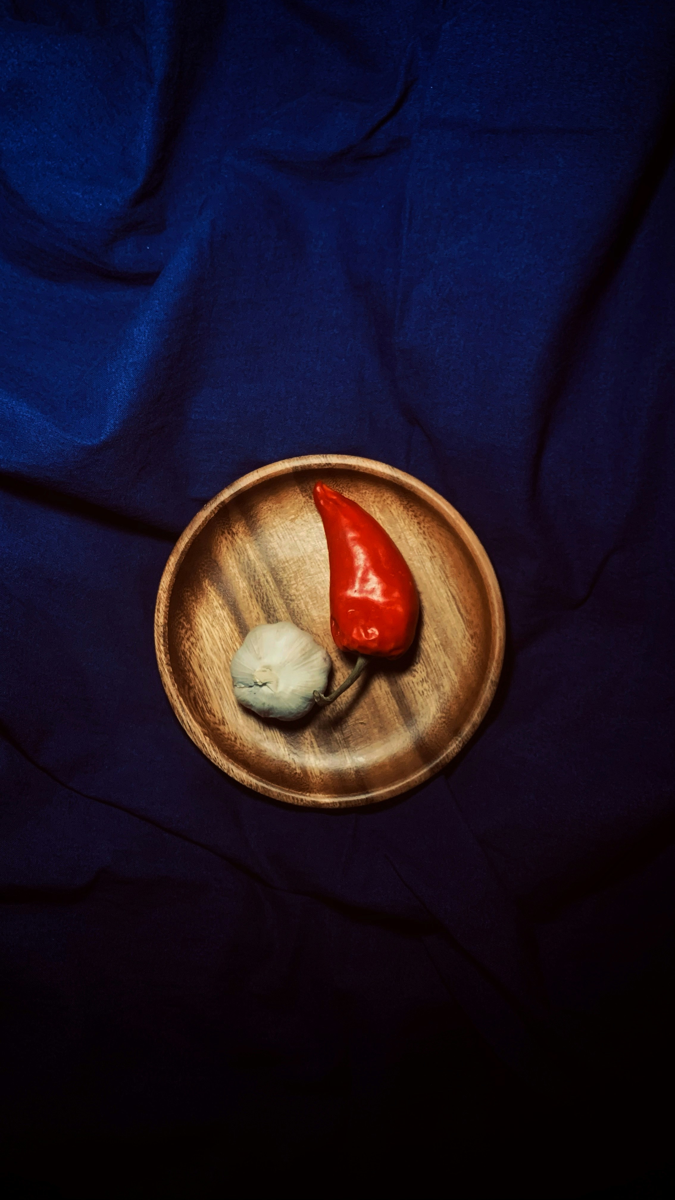 Crimson Pepper on a Wooden Plate Against Velvet Indigo