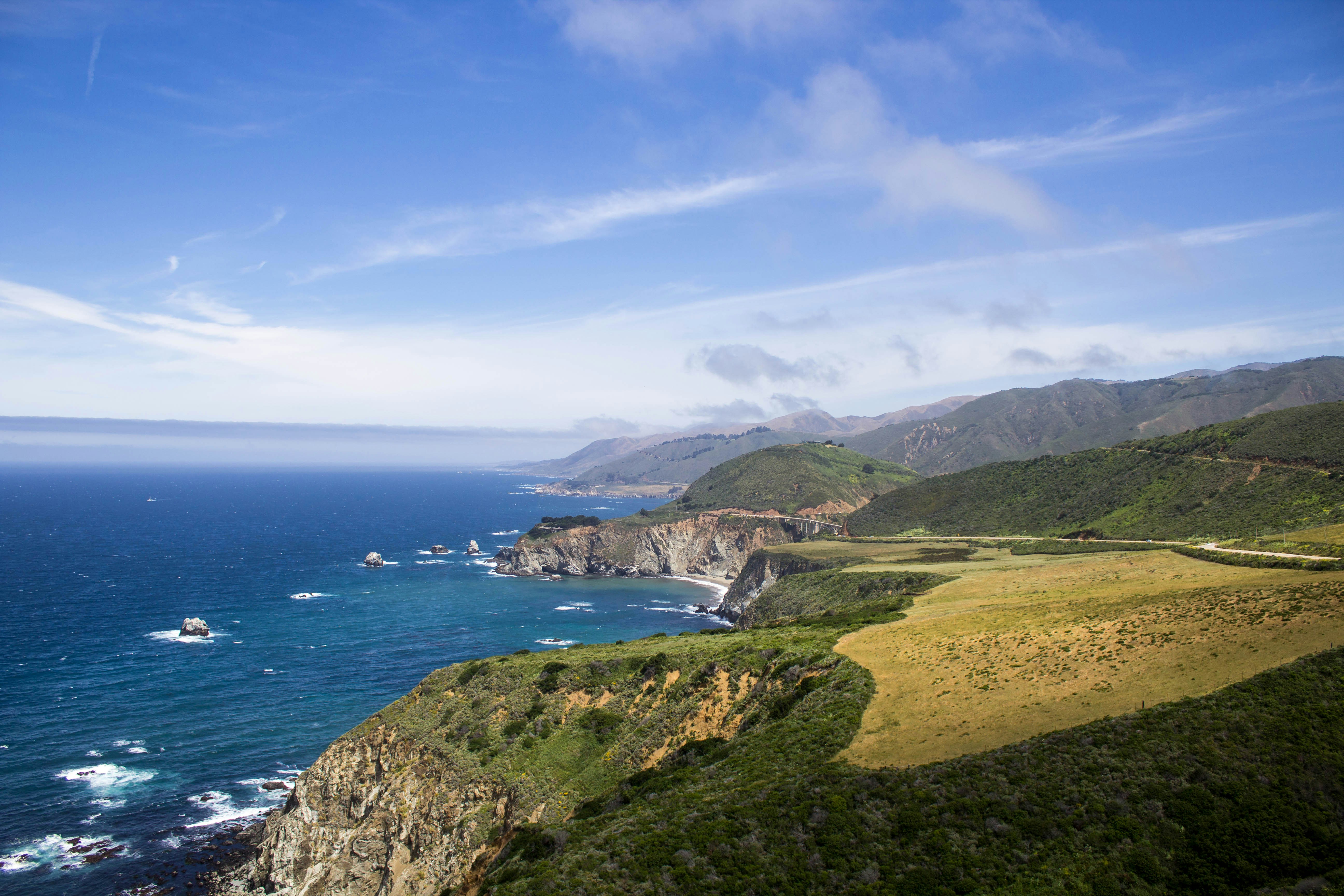 Expansive coastline with rugged cliffs and lush greenery under a clear blue sky.