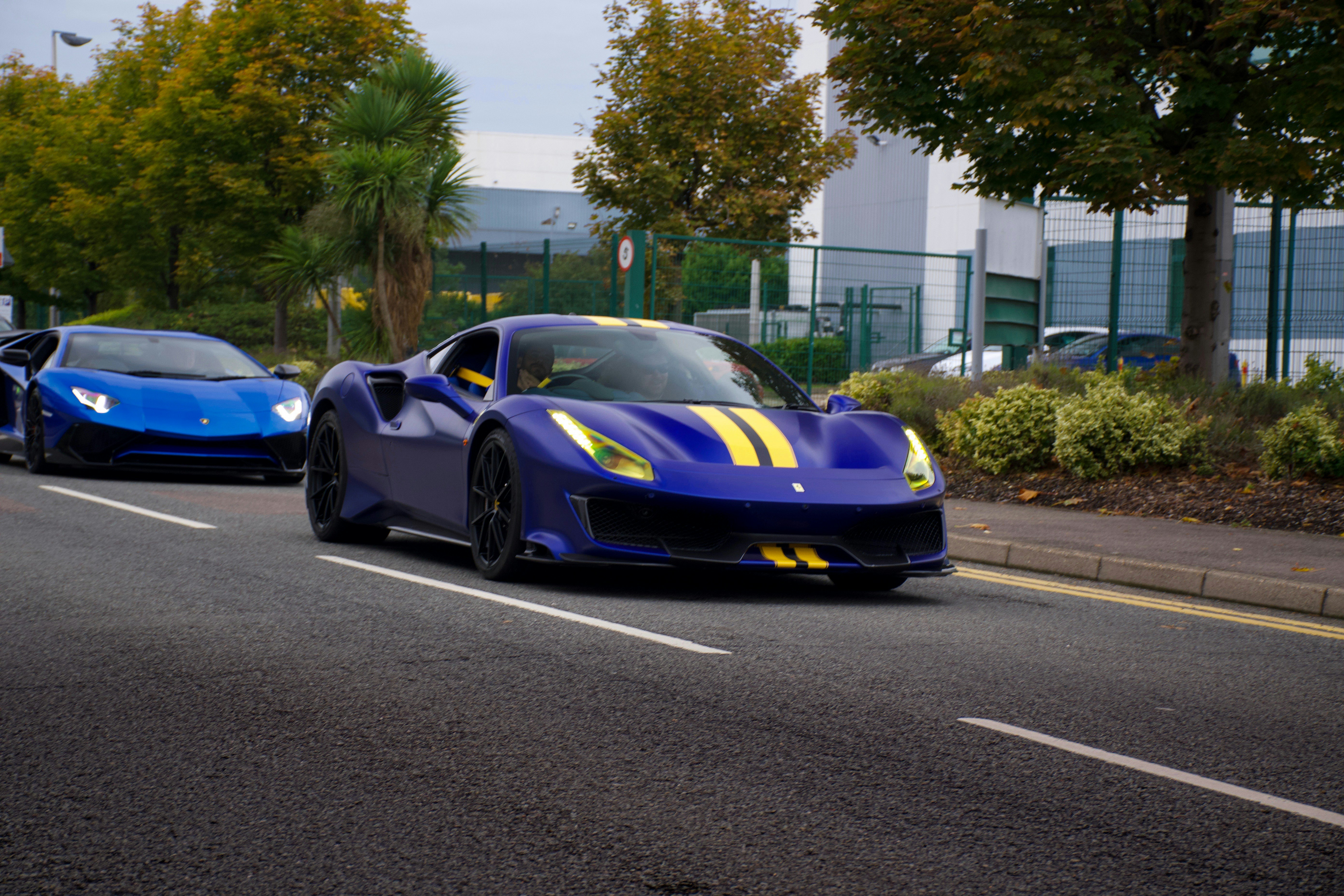 Azure Stripes in Motion: Blue Ferrari Leads a City Street Parade
