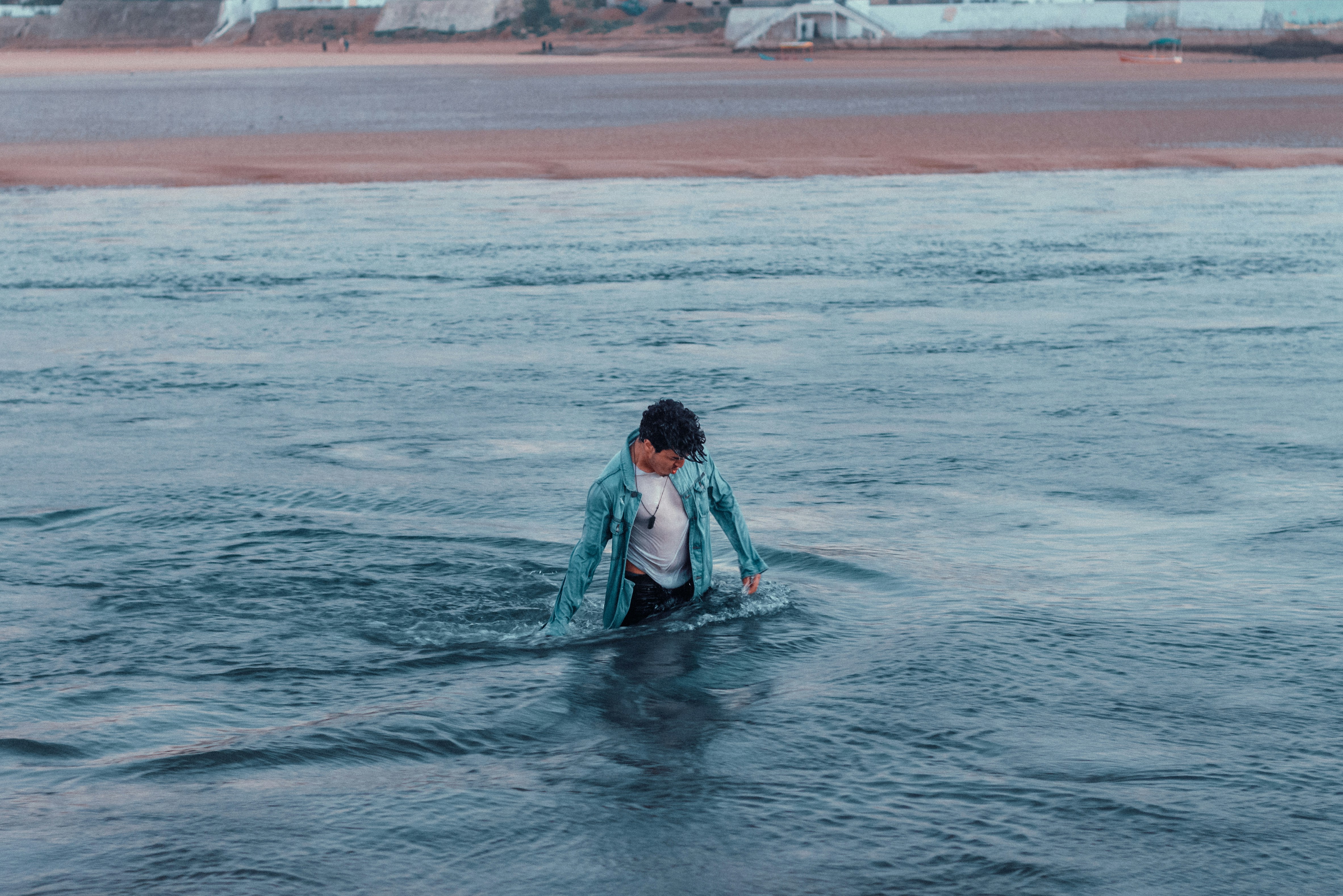 Teal-Clad Figure Wades Waist-Deep Through Quiet Coastal Blues