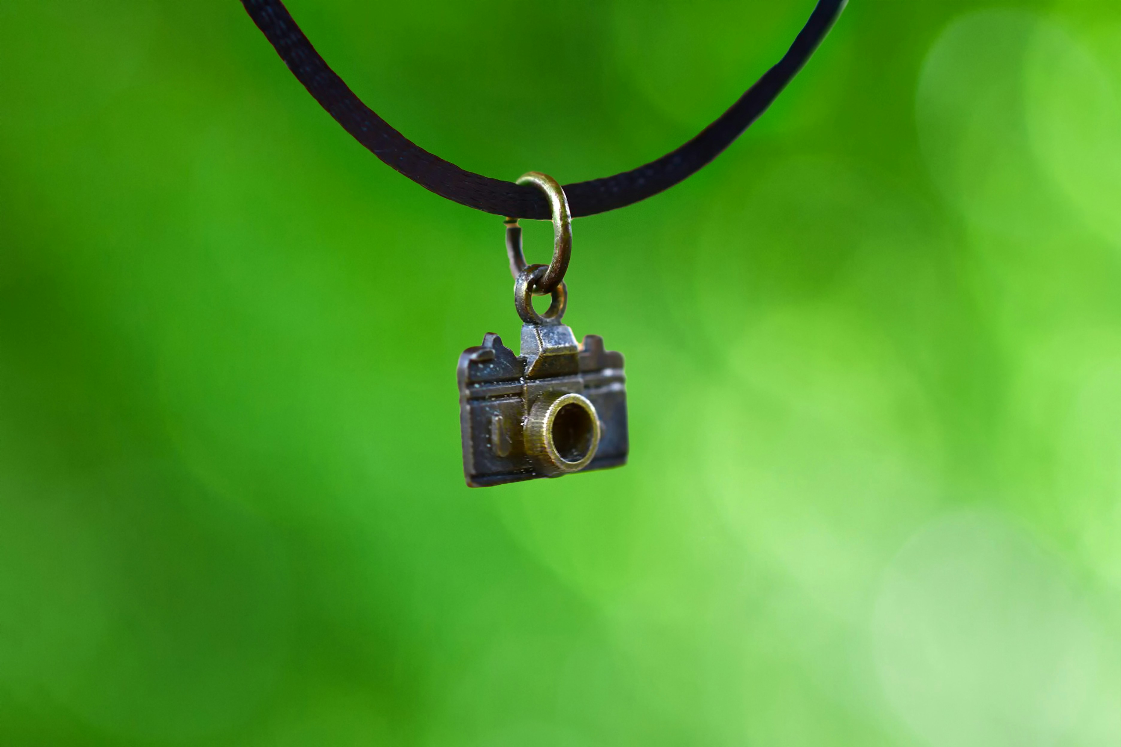 Tiny Vintage Camera Pendant Hovering in Emerald Bokeh