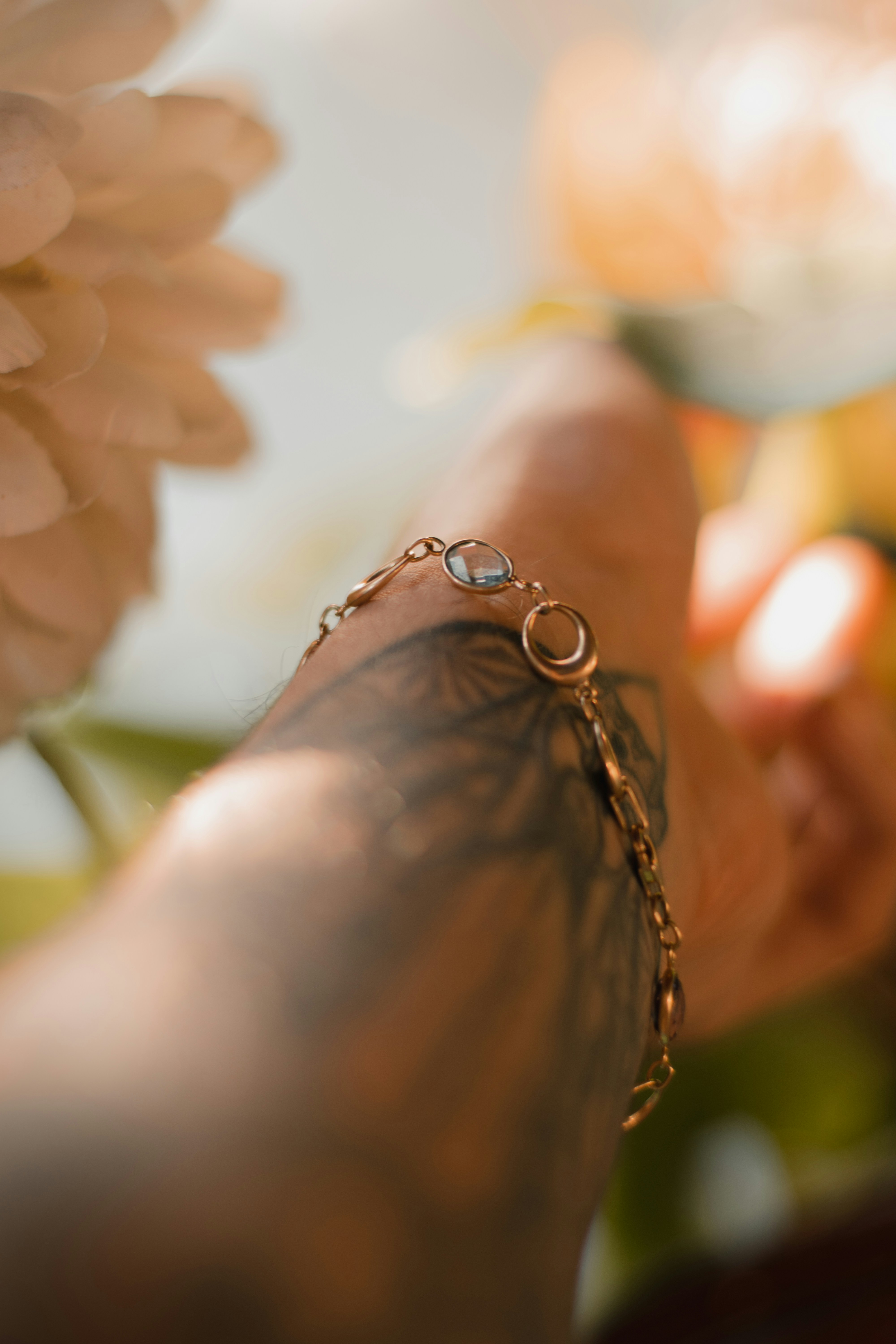 Tender Moment: A bracelet and tattoo in soft focus against a floral backdrop