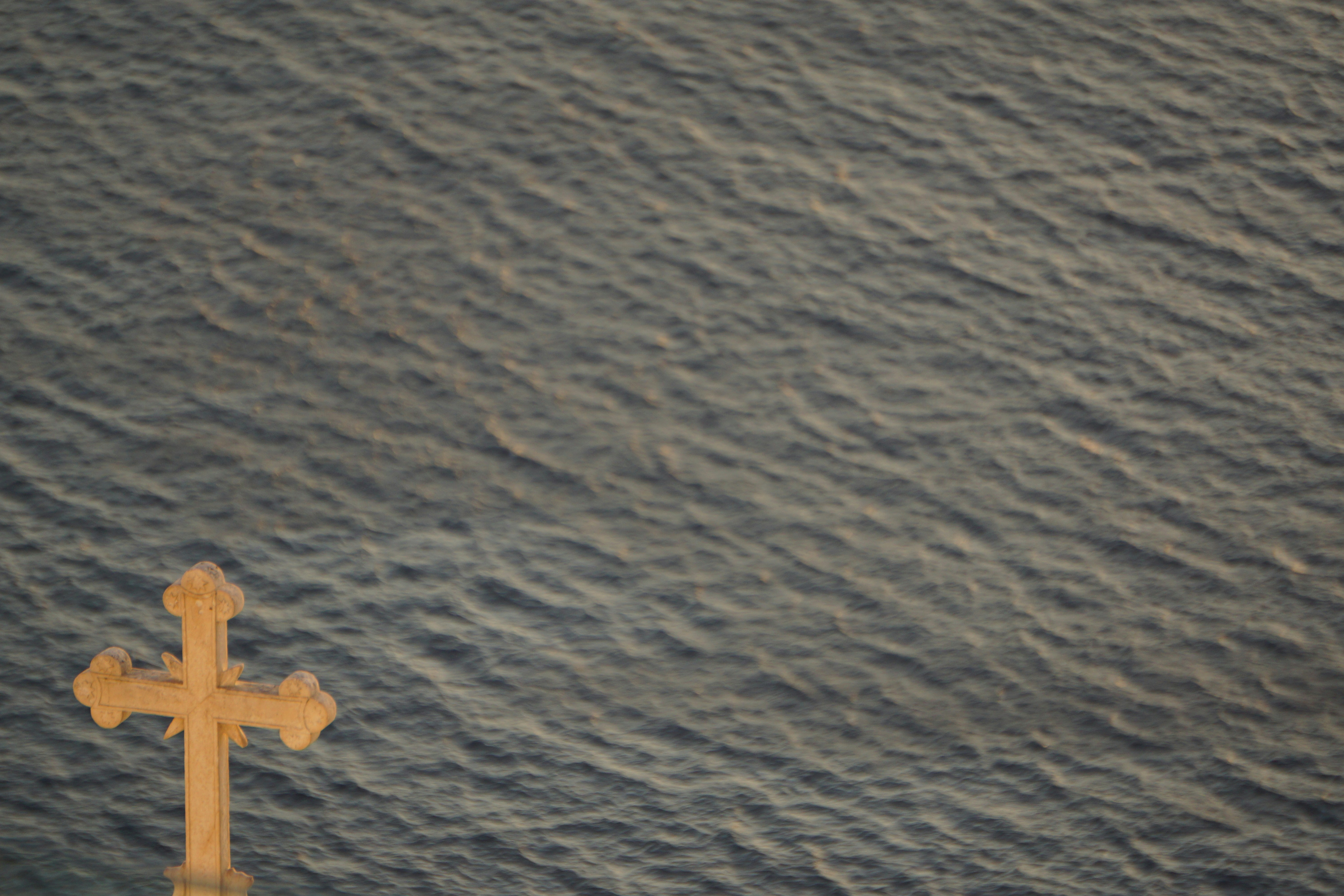 Cross at Dawn's Edge Over Rippled Sea
