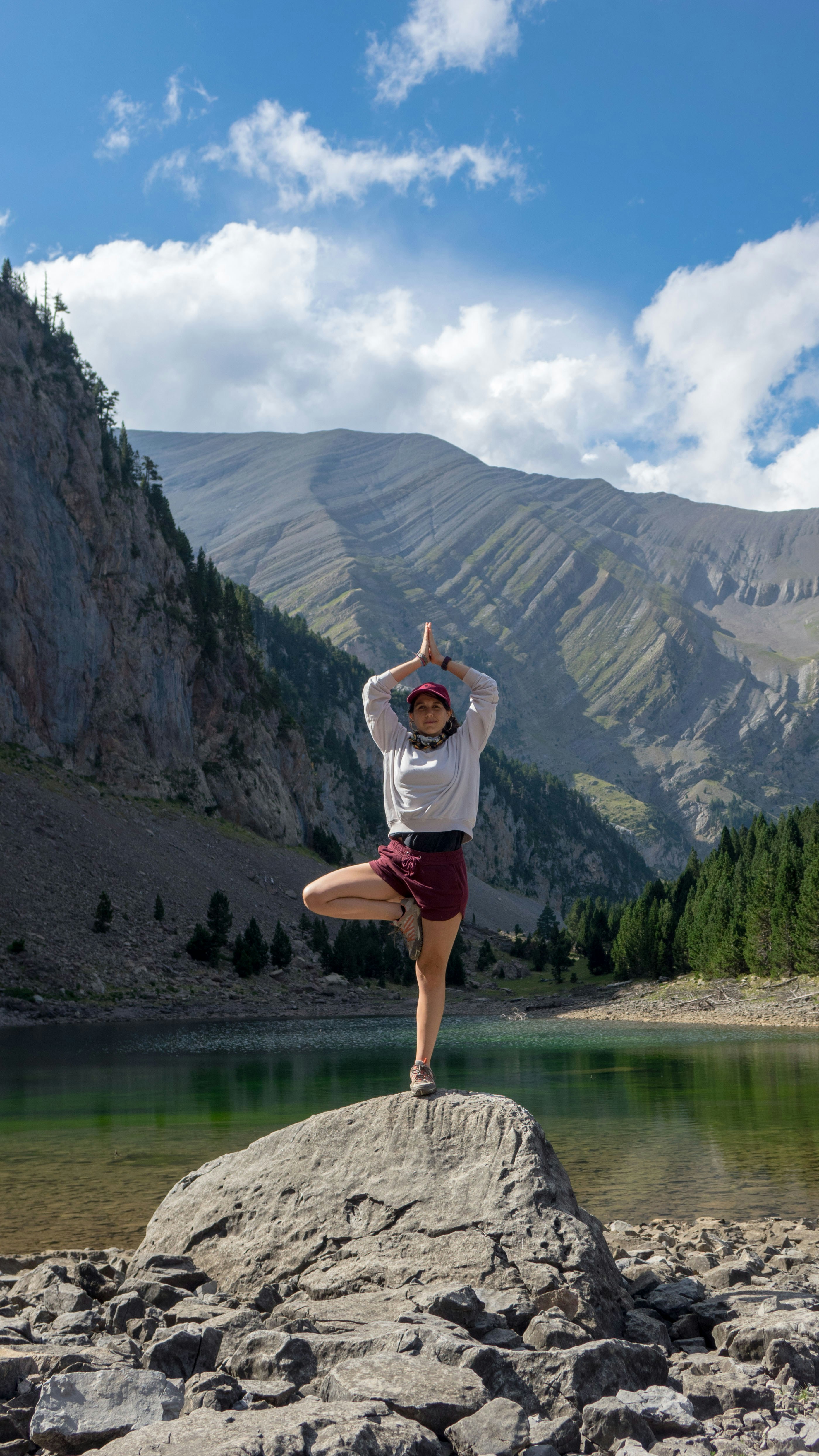 Woman in white shirt and red shorts standing on rock near lake during ...