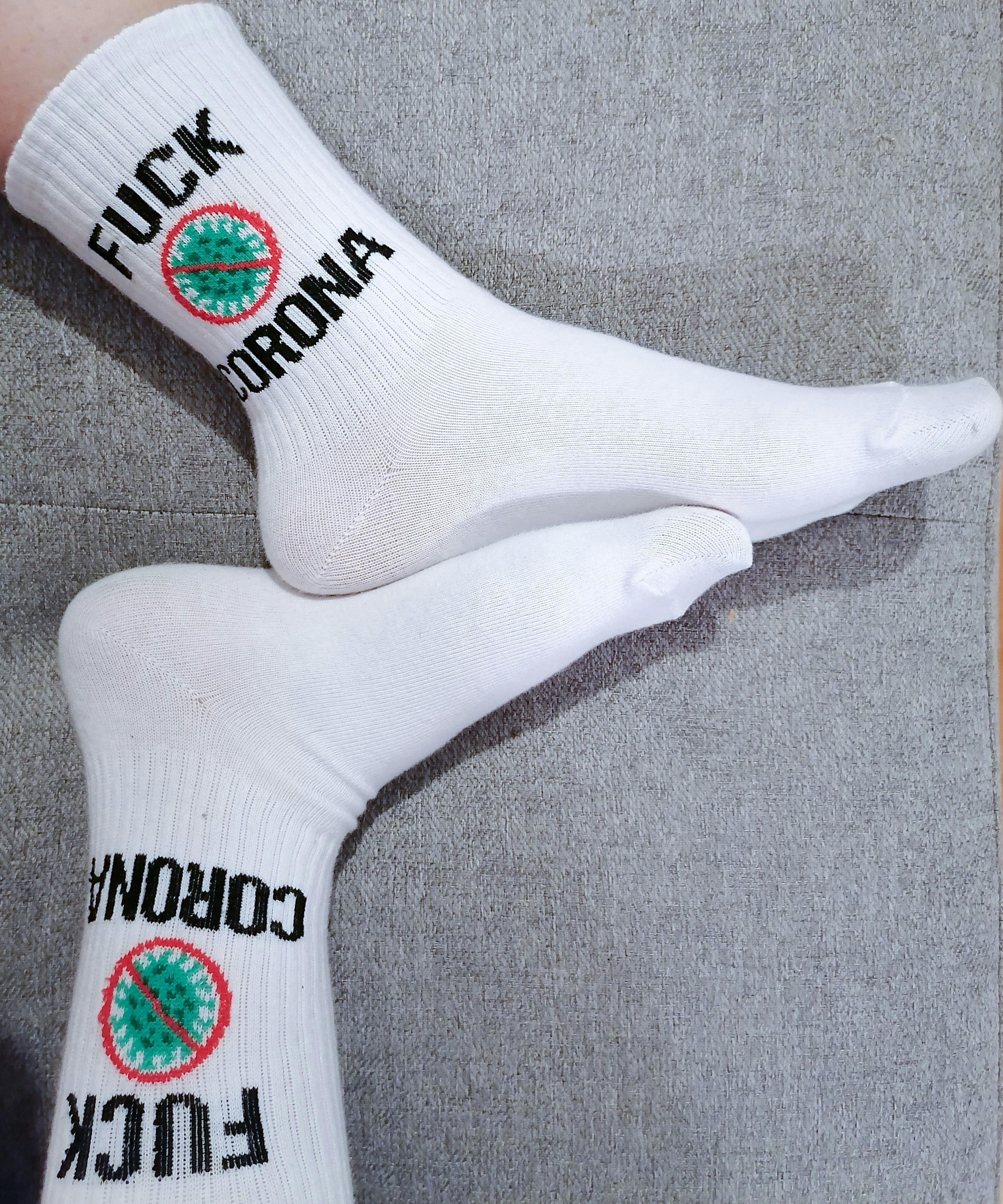 White socks featuring bold text and a graphic symbol expressing a humorous take on the pandemic. The design conveys a sense of rebellion and lightheartedness.