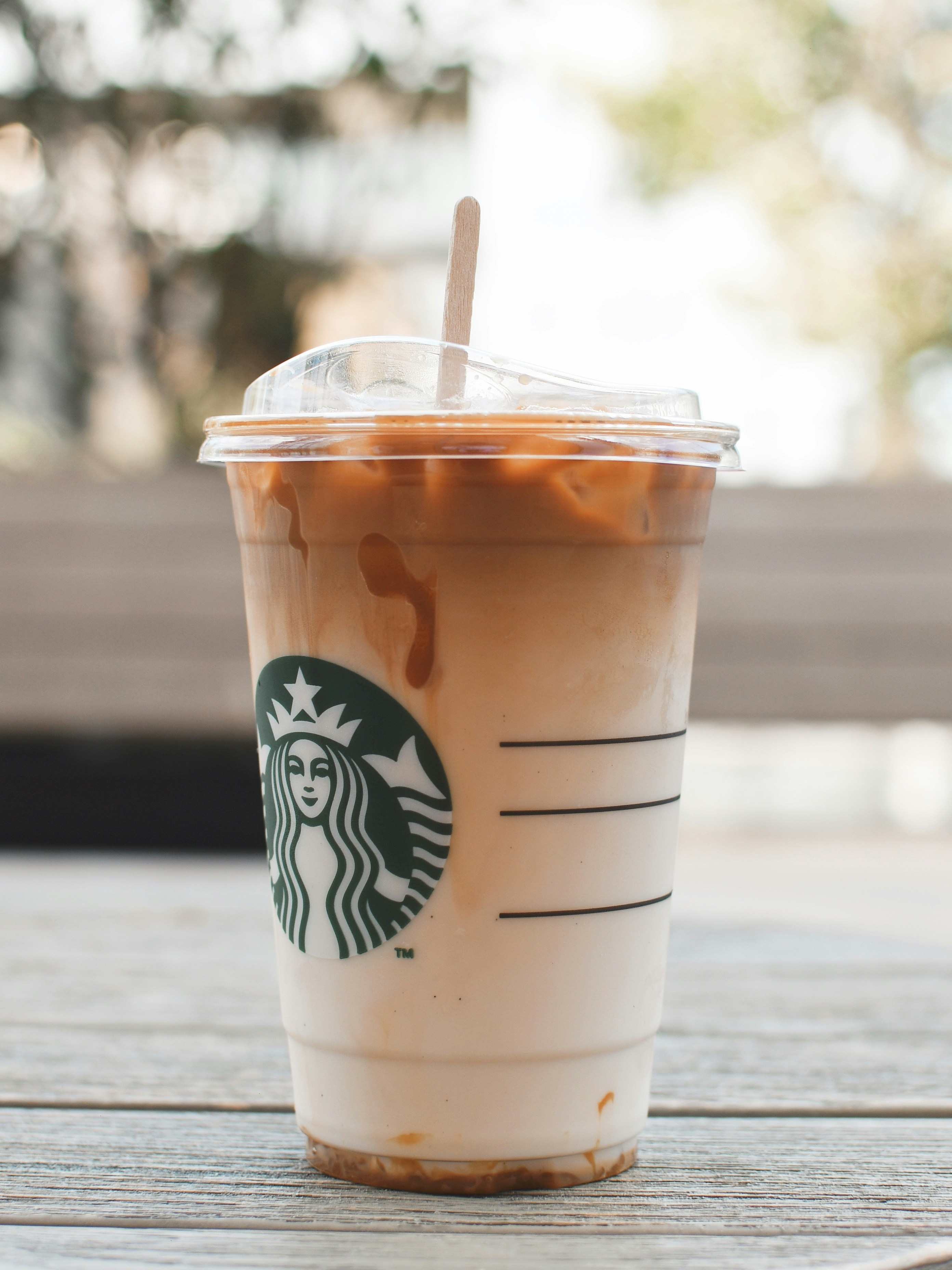 Caramel Cascade in Sunlit Glass: A Starbucks Iced Latte on a Weathered Table