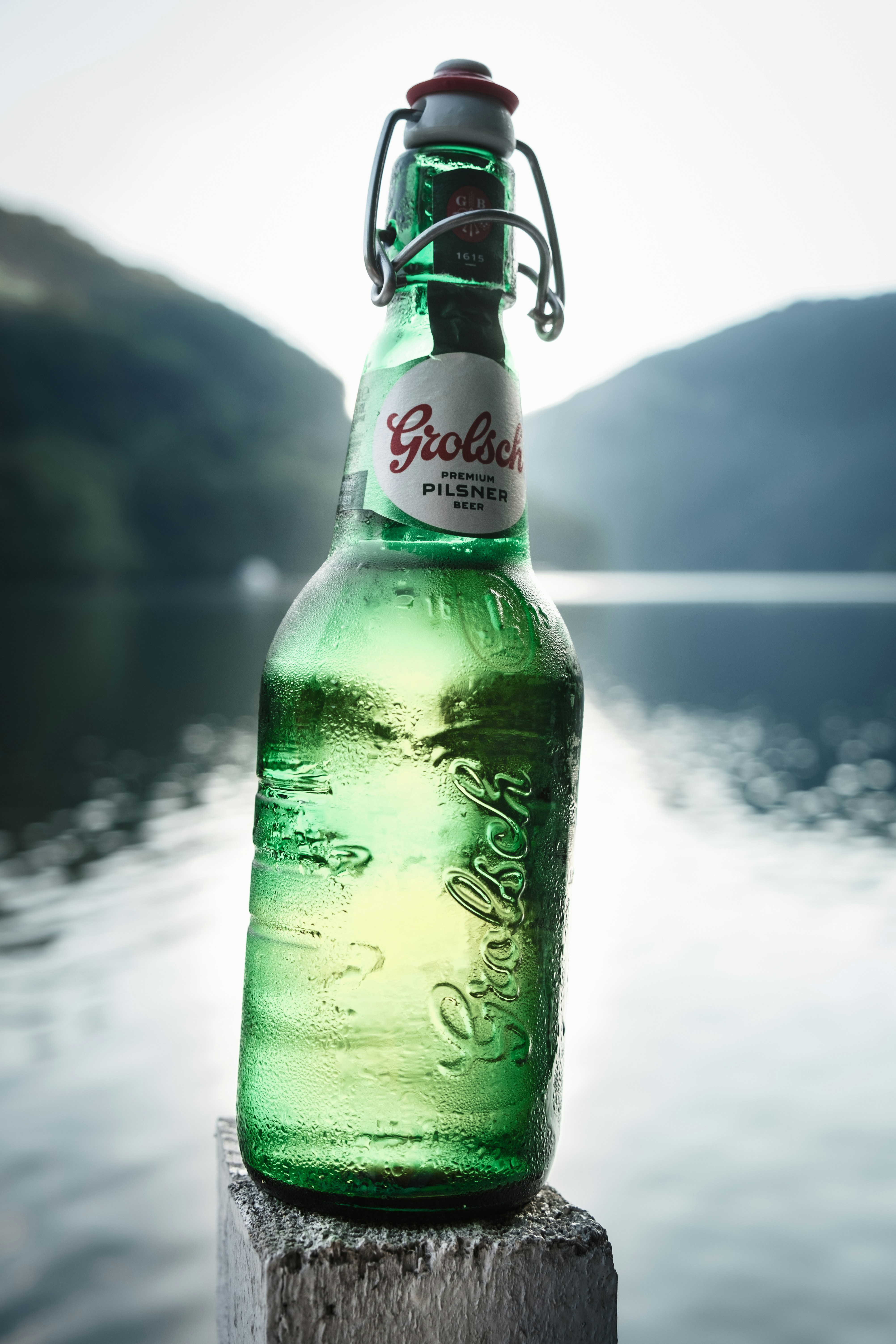 Grolsch on a Weathered Post: A Green Bottle Framing a Mountain Lake