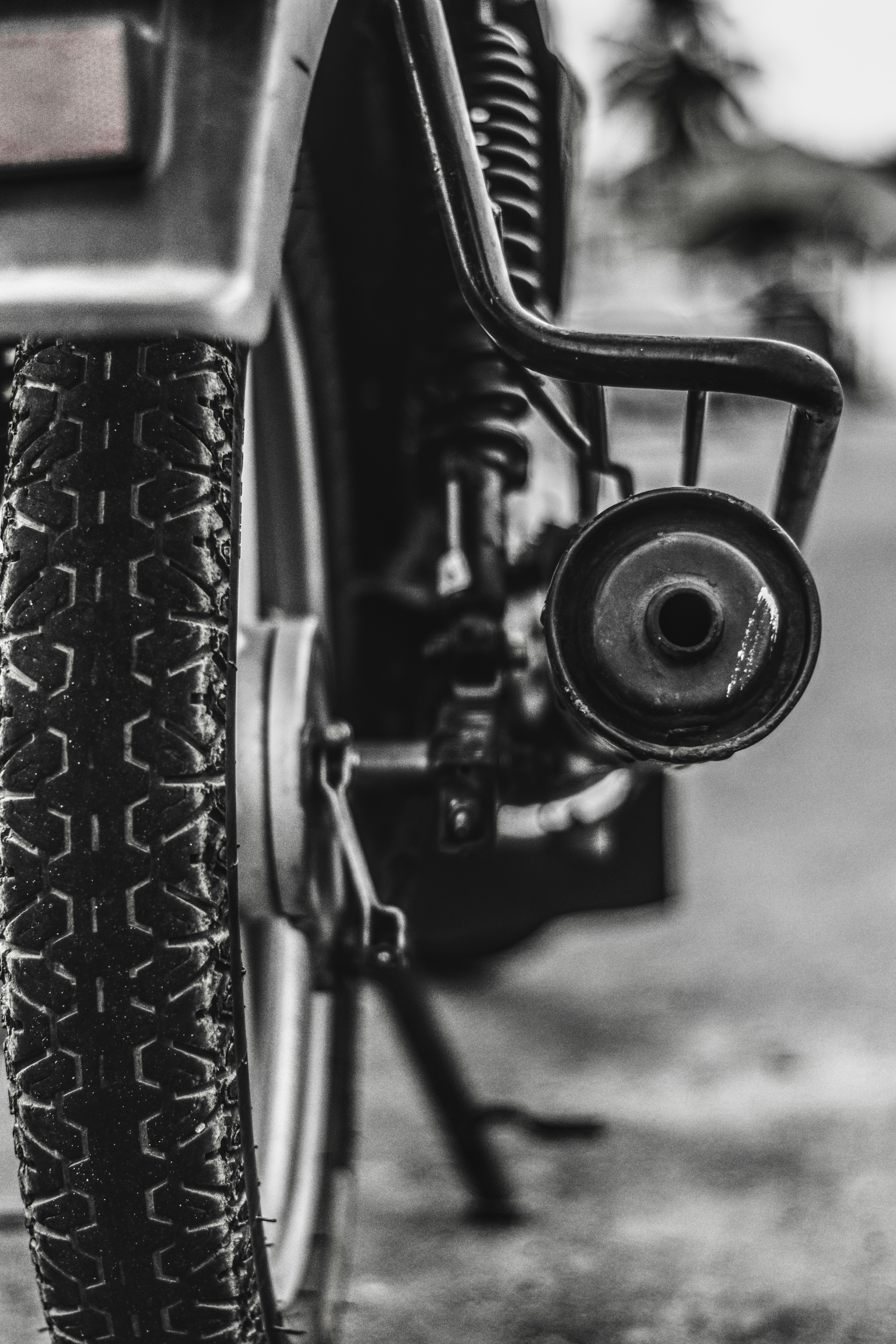 Close-up of a motorcycle's rear wheel and exhaust, showcasing the intricate details of the tire tread and metallic components.