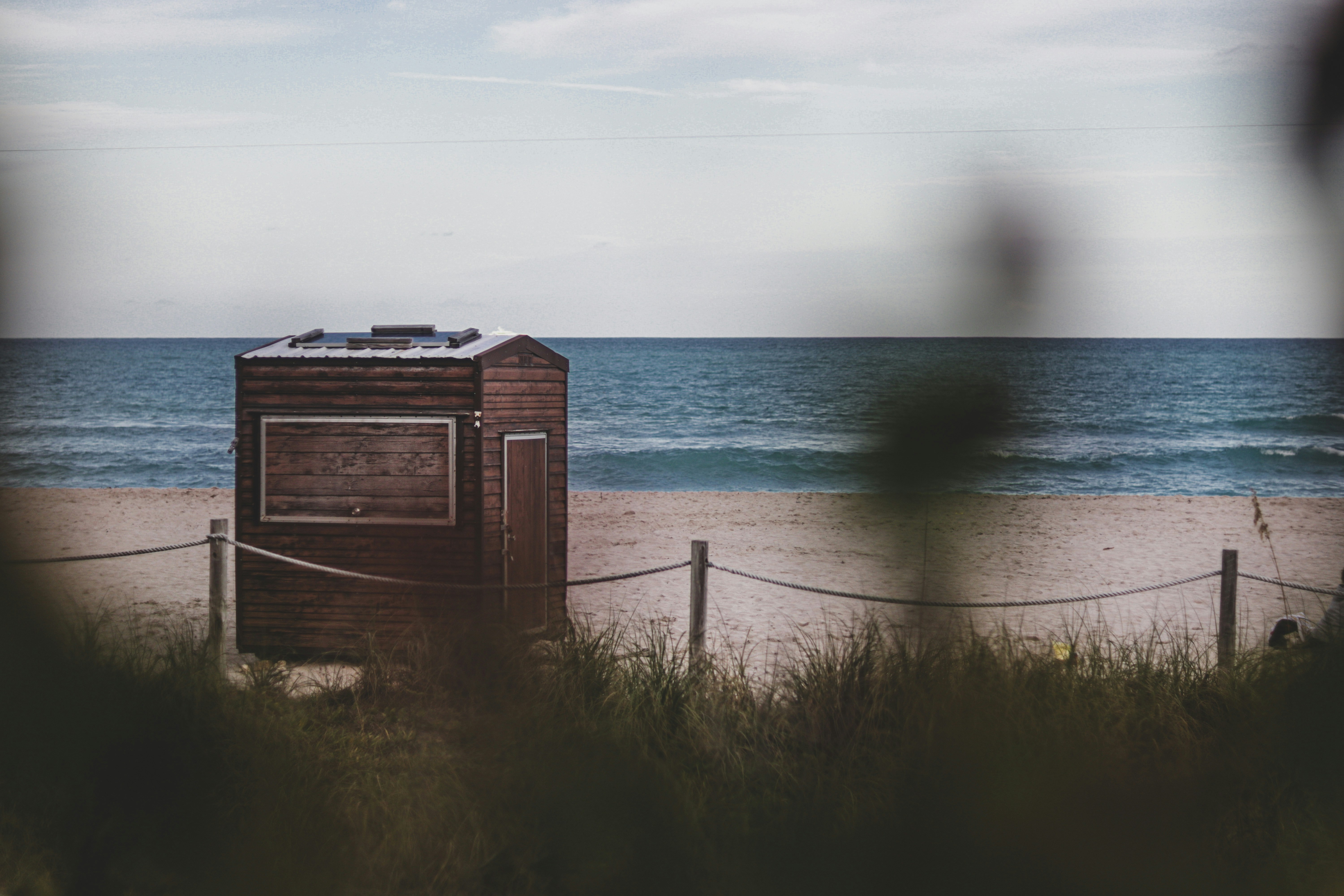 Dune-Edge Shack: Weathered Beach Refuge Framed by Grass